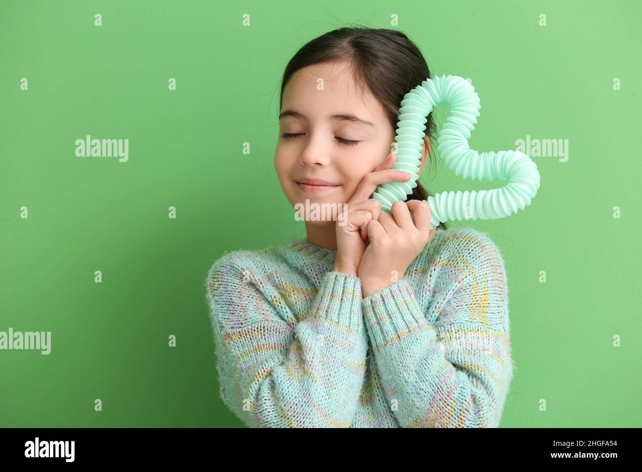 Little girl with blue Pop Tube on green background Stock Photo - Alamy