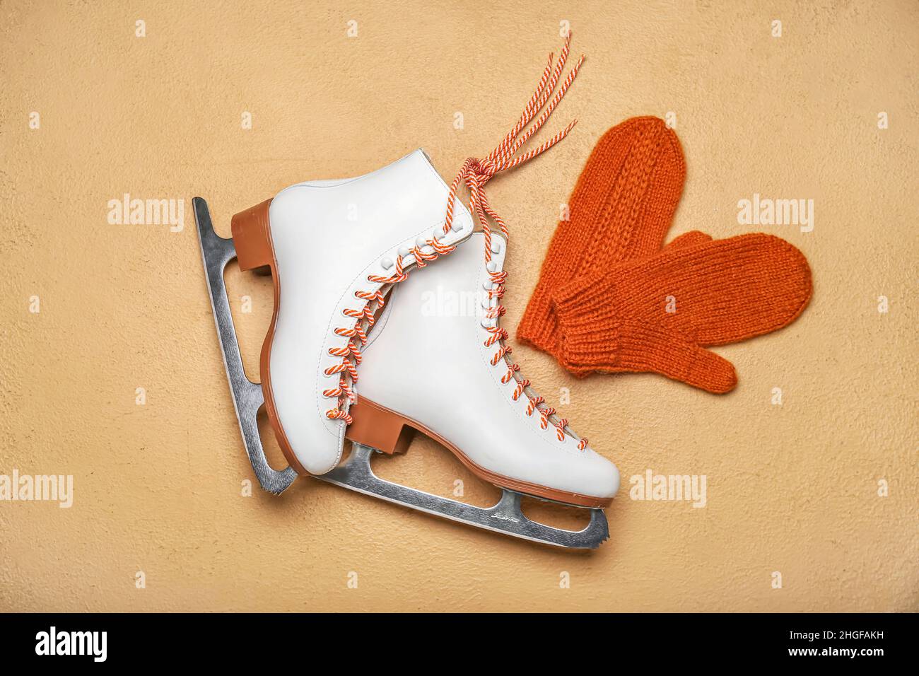Ice skates and mittens on beige background Stock Photo - Alamy