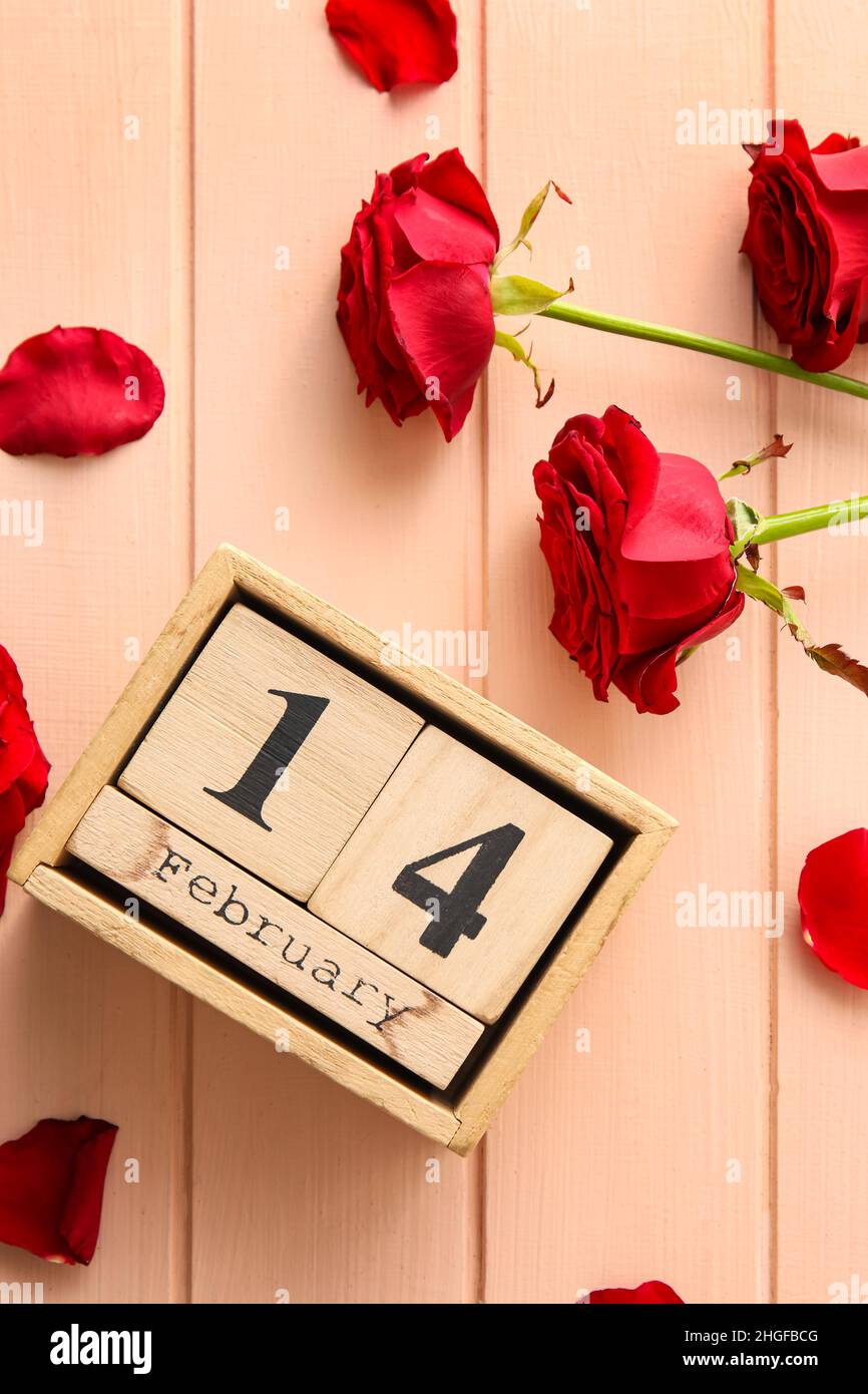 Calendar with date of Valentines Day and red roses on wooden background ...