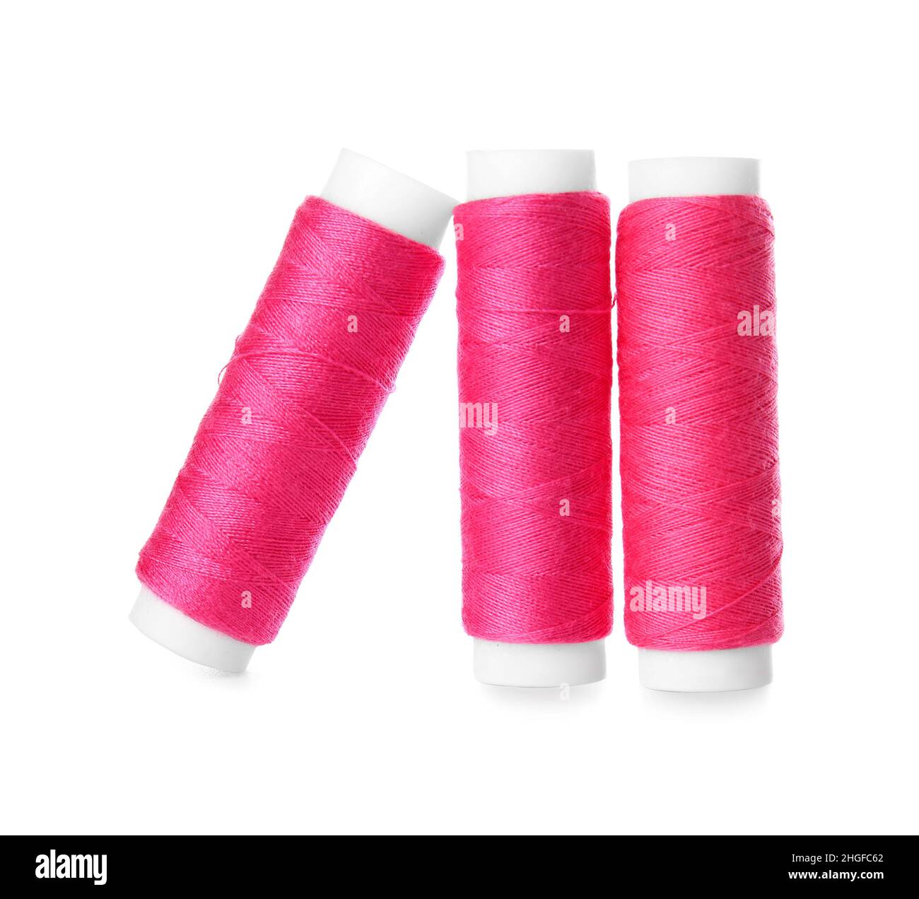 Pink sewing thread spools on white background Stock Photo - Alamy