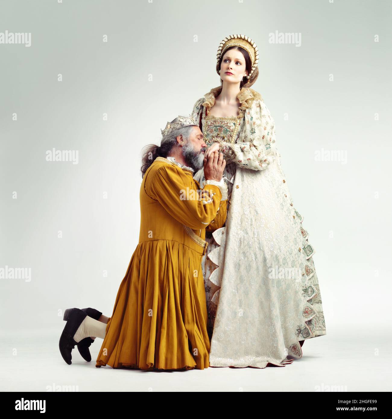 Behind every great man.... Studio shot of a king kneeling and kissing ...