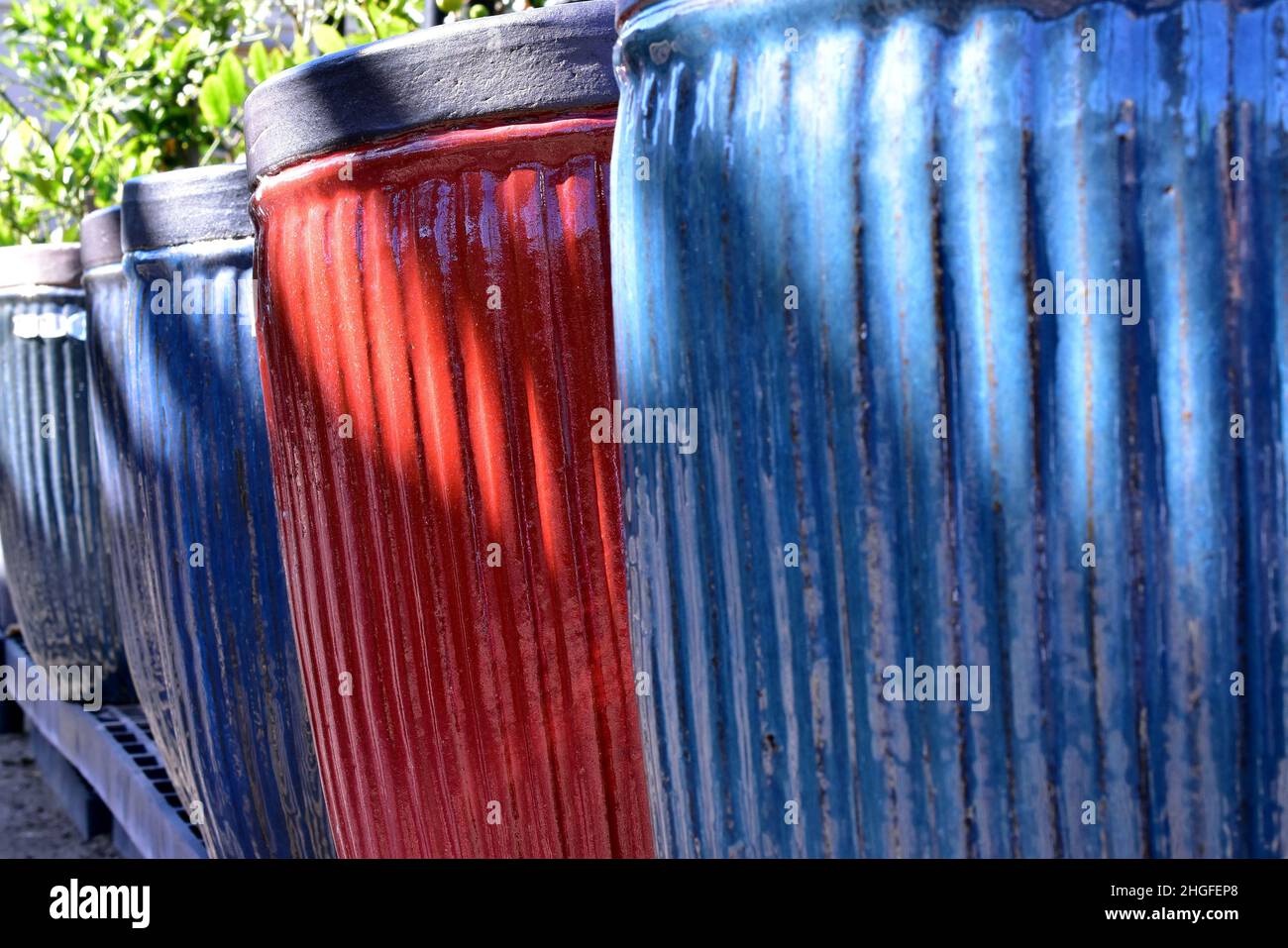 Line of Red and Blue Tapered Ceramic Containers with Lids Outside Stock ...