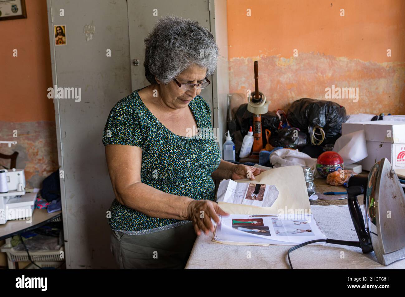 Grey-haired Latinx woman looks through sewing patterns in her ...