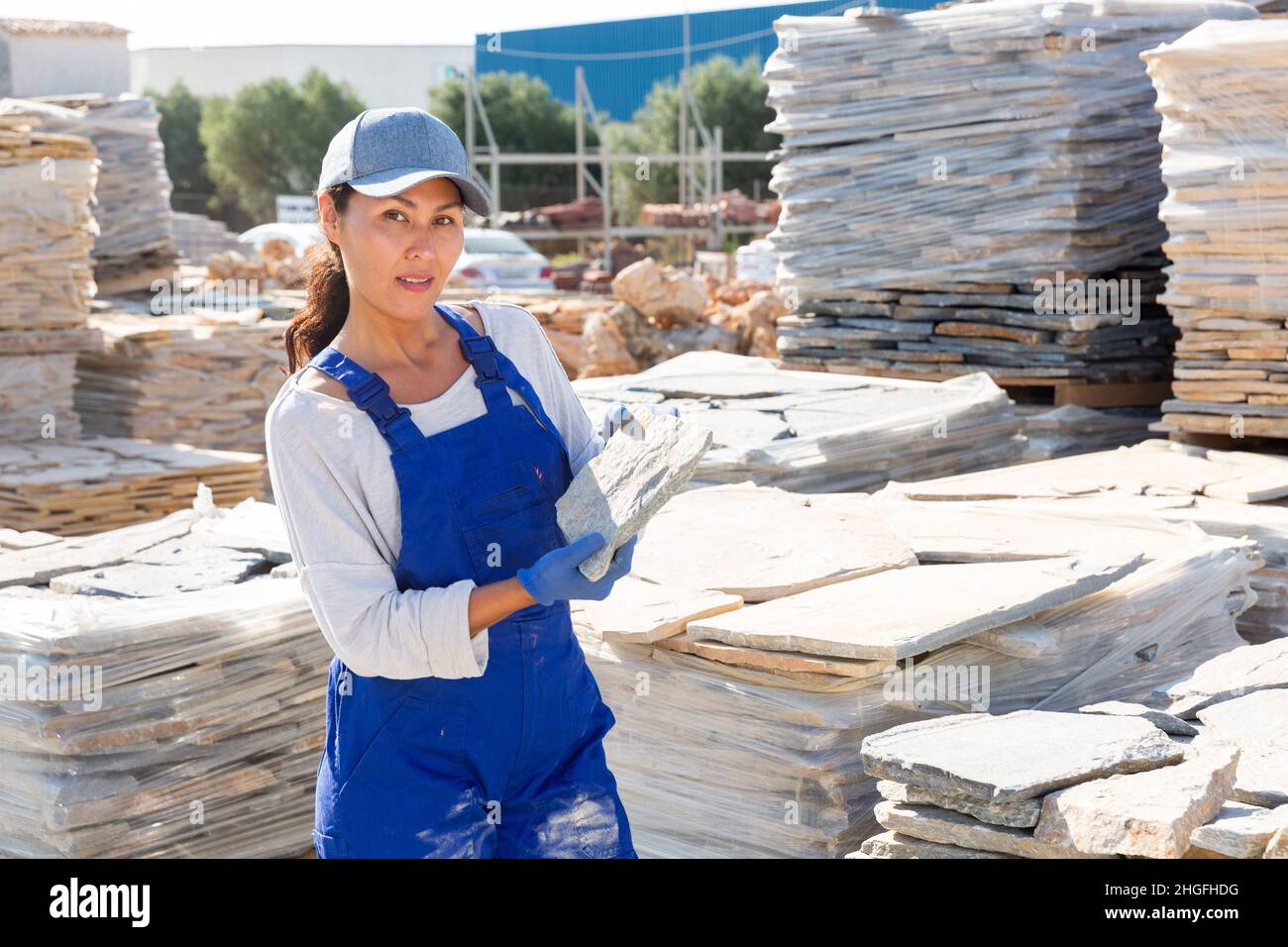 Female construction store clerk demonstrates natural stone tiles on ...