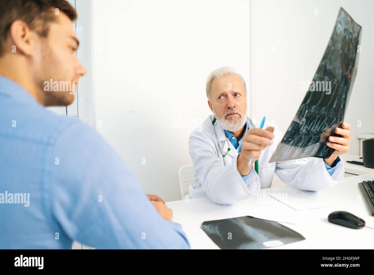 View from back of mature male doctor radiologist explaining results of ...