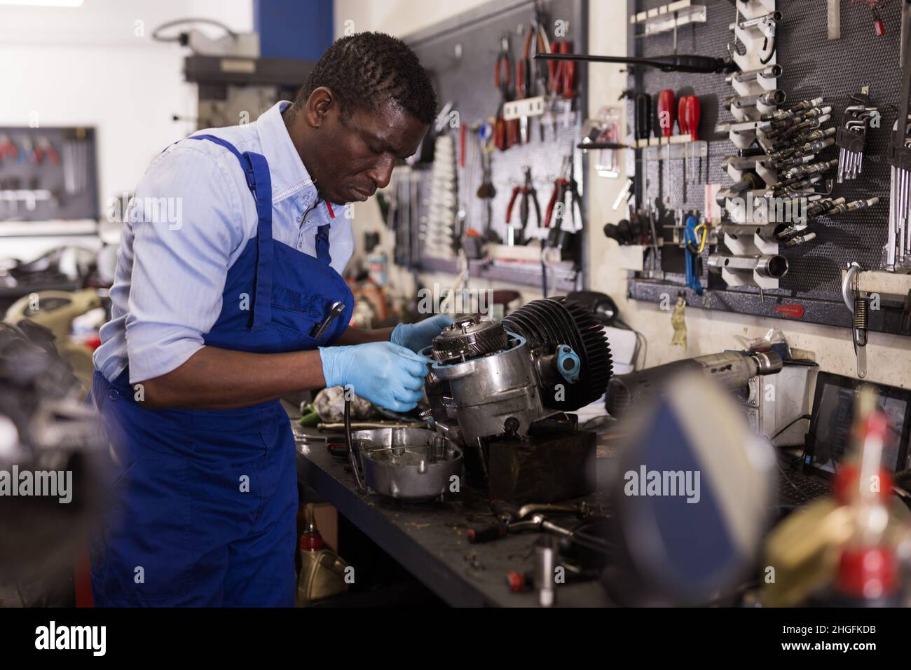 Mechanic in overalls repairing a motorcycle engine in a garage Stock ...