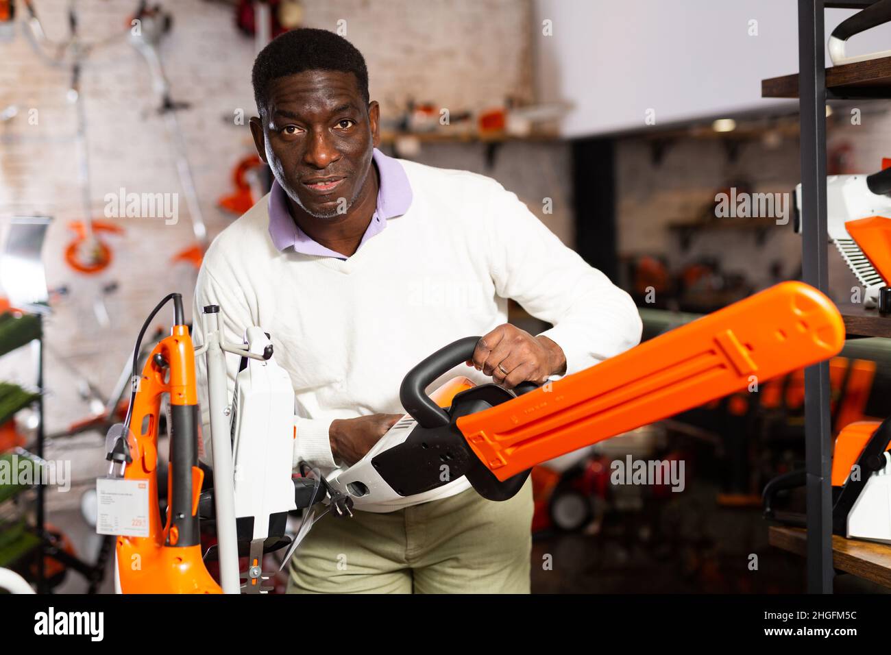 African american man chooses chainsaw at garden tool store Stock Photo ...