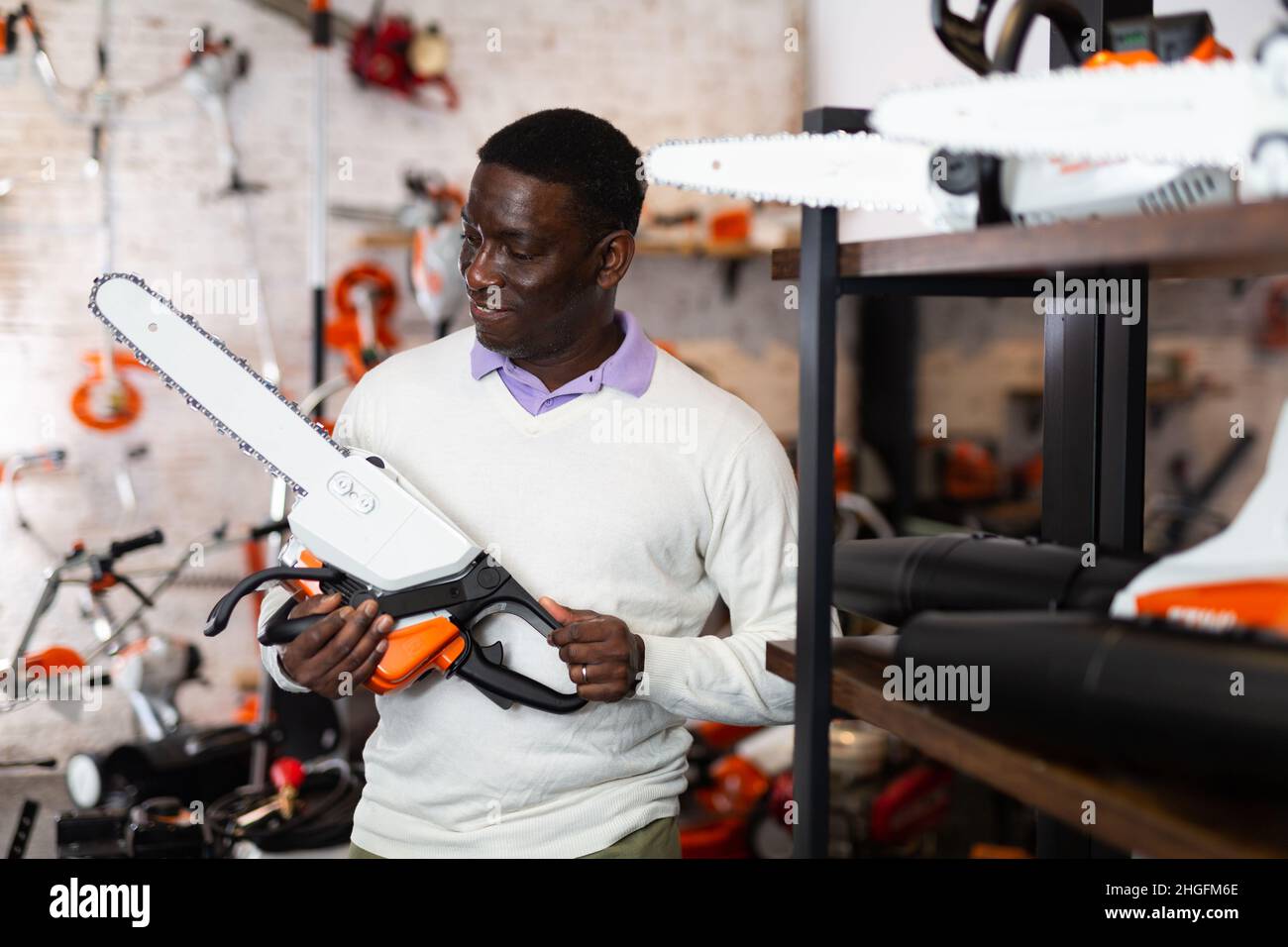 African american man chooses chainsaw at garden tool store Stock Photo ...