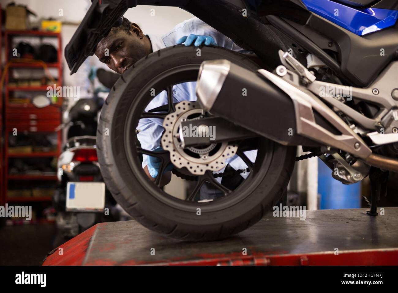 African american worker inspects the wheel of a motorcycle Stock Photo ...