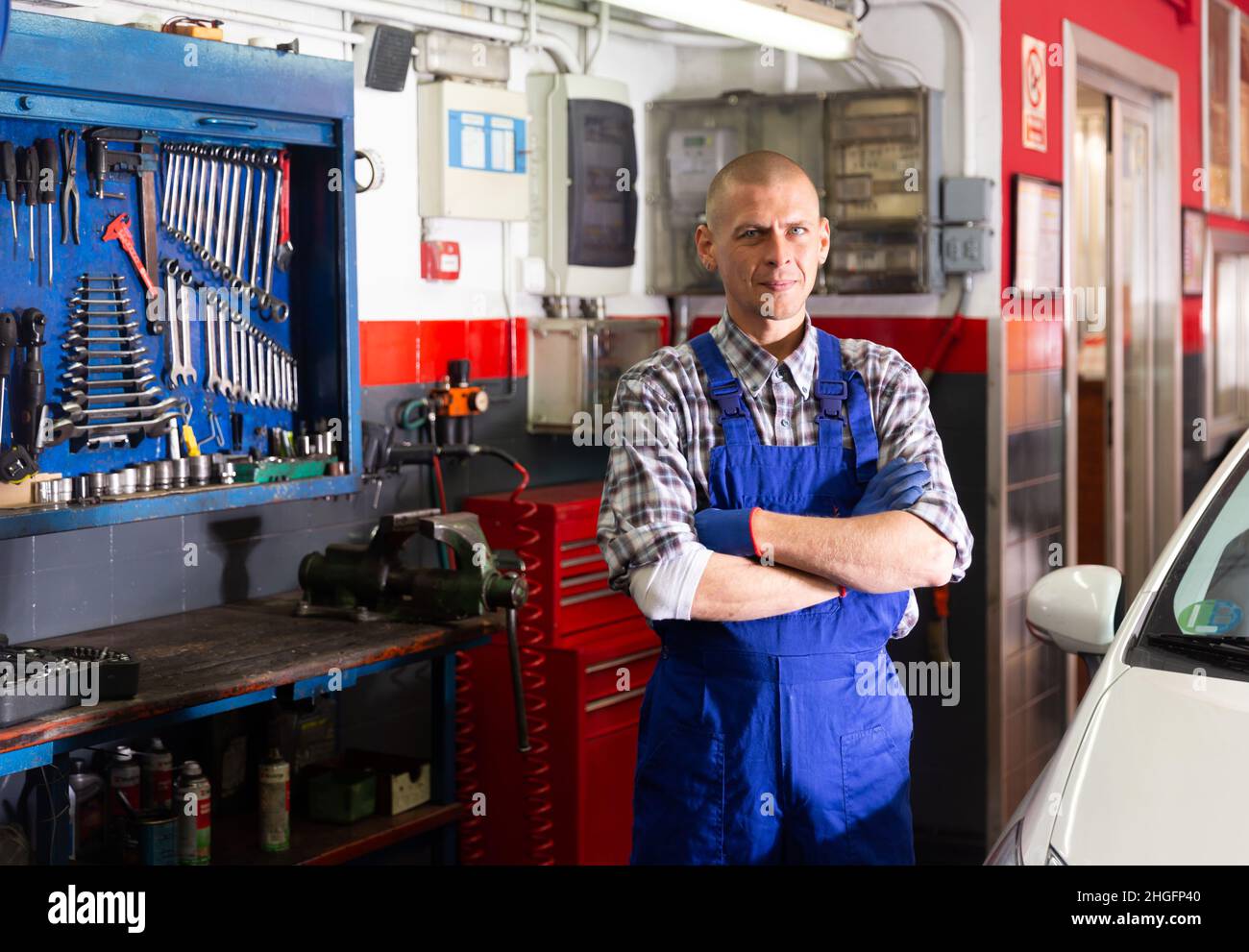 Portrait of man car mechanician standing near repairable car in auto ...