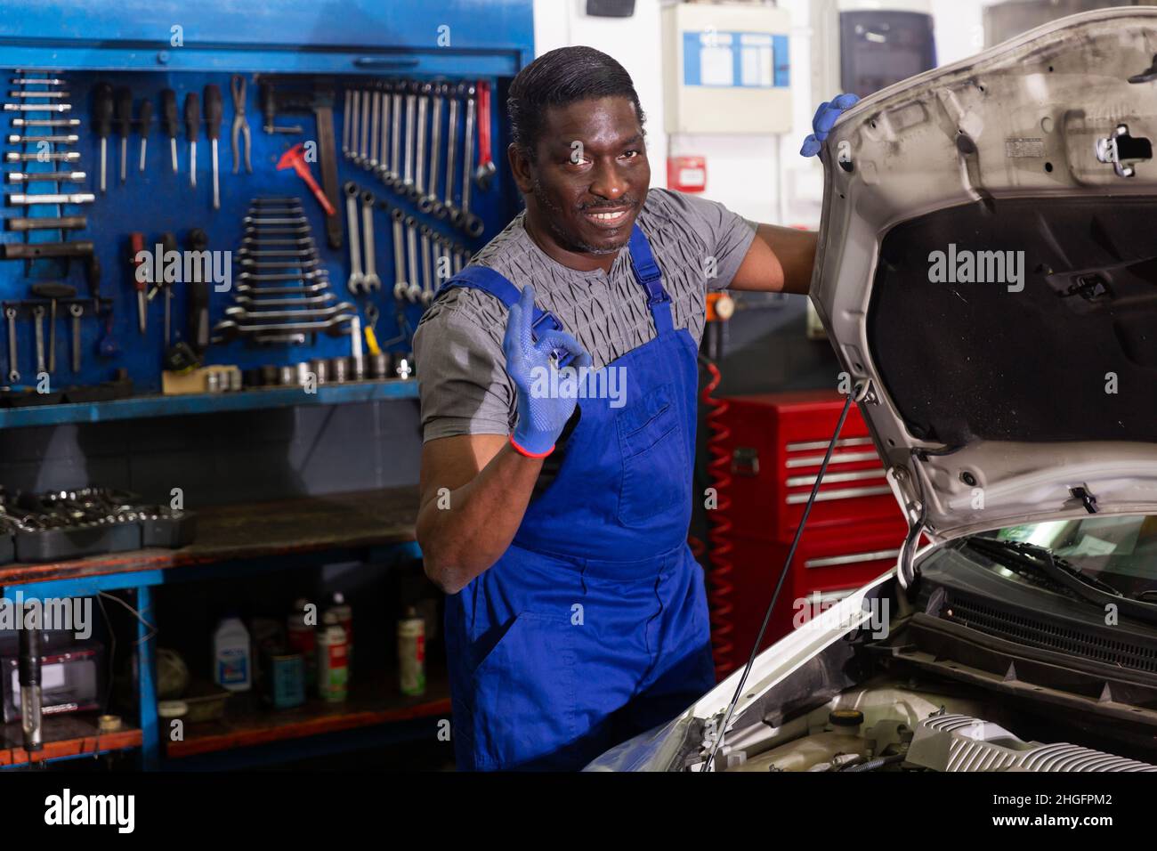 Professional american mechanic man in uniform repairing car engine ...