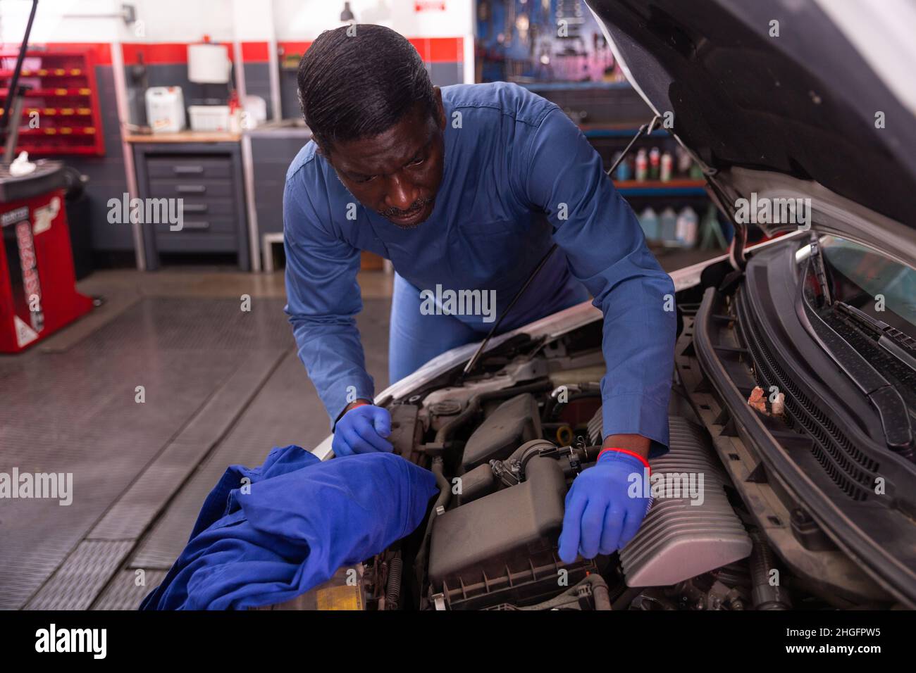 Professional american mechanic man in uniform repairing car engine ...