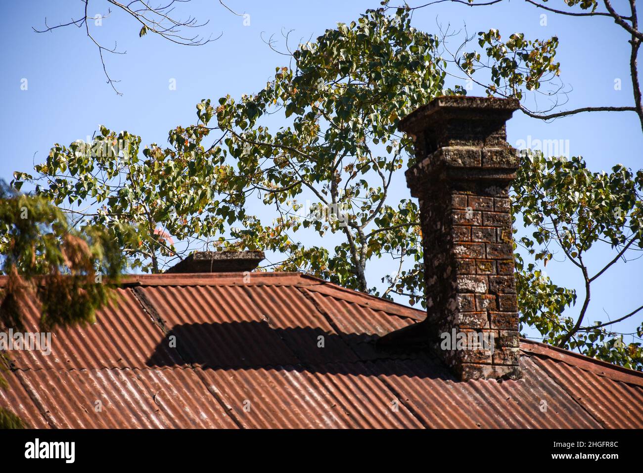 Stone chimney on a slanted red metallic roof without smoke Stock Photo ...