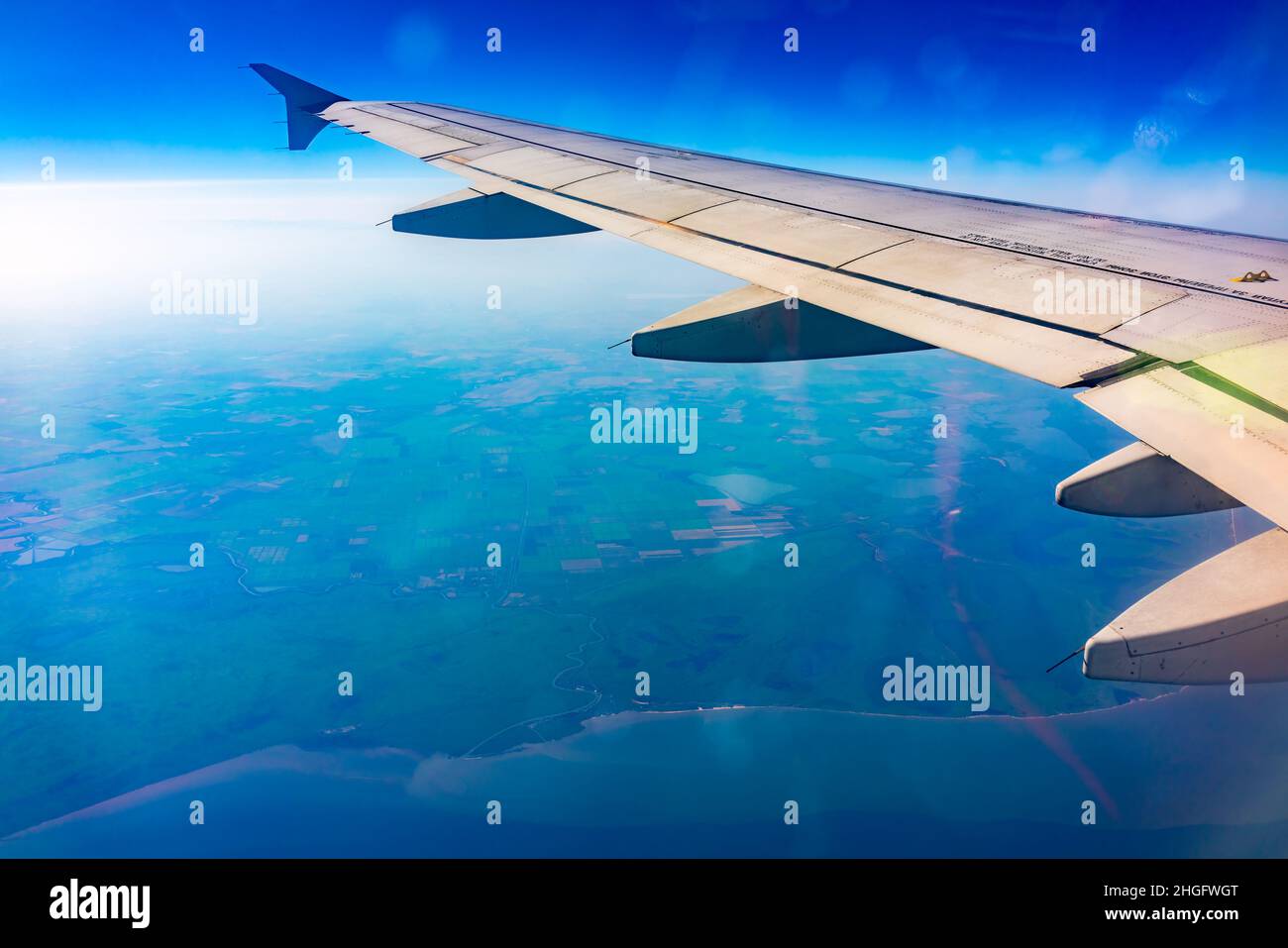 View from the airplane window at a beautiful blue clear sky, earth, sea ...