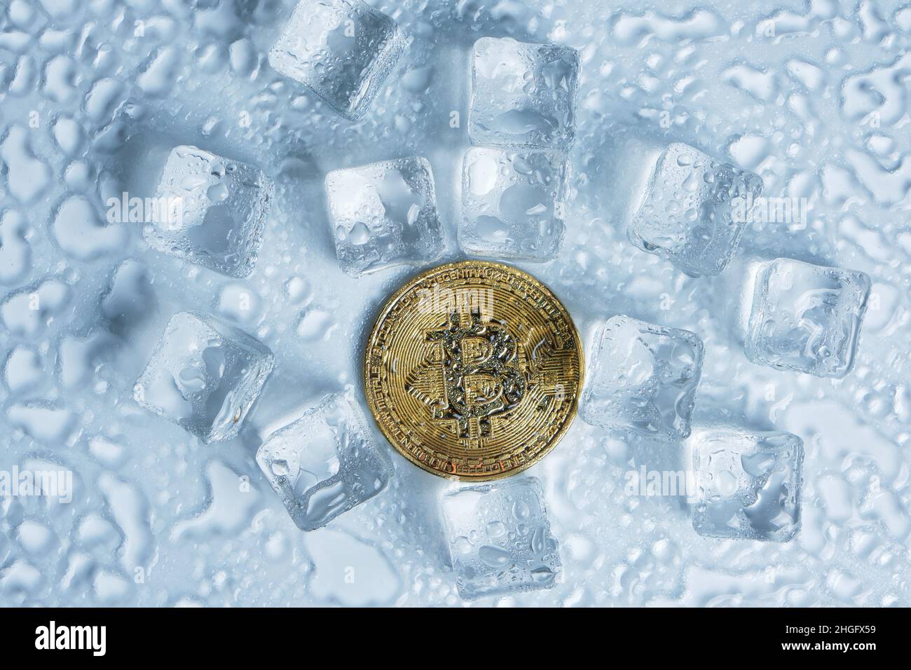 Bitcoin coin middle melting ice cubes and water drops on light ...
