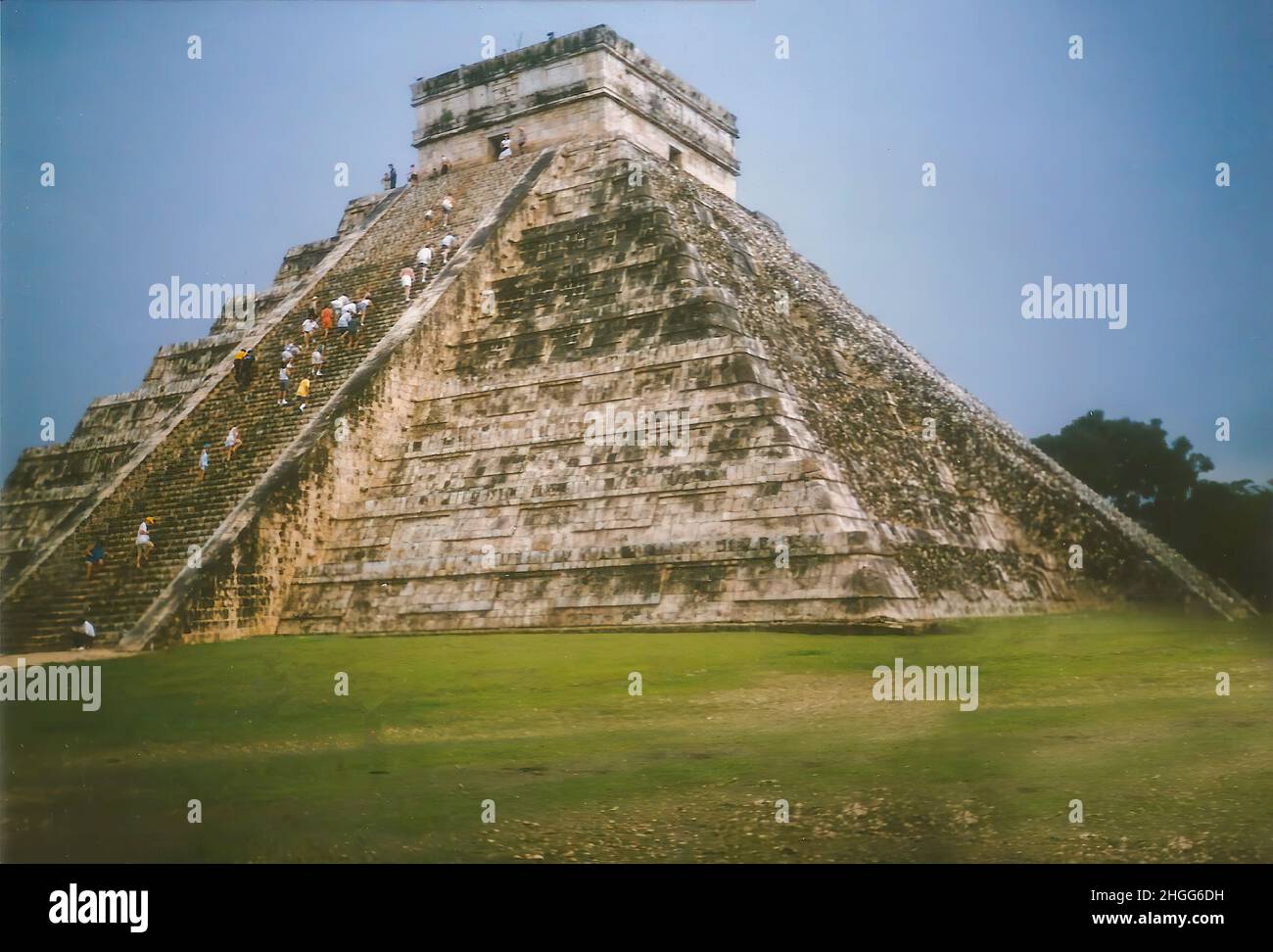 Tourists climbing the main pyramid of the Mayan ruins at Chichen Itza ...