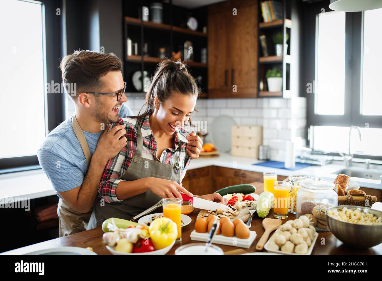 Happy people, couple cooking food together in their loft kitchen at ...