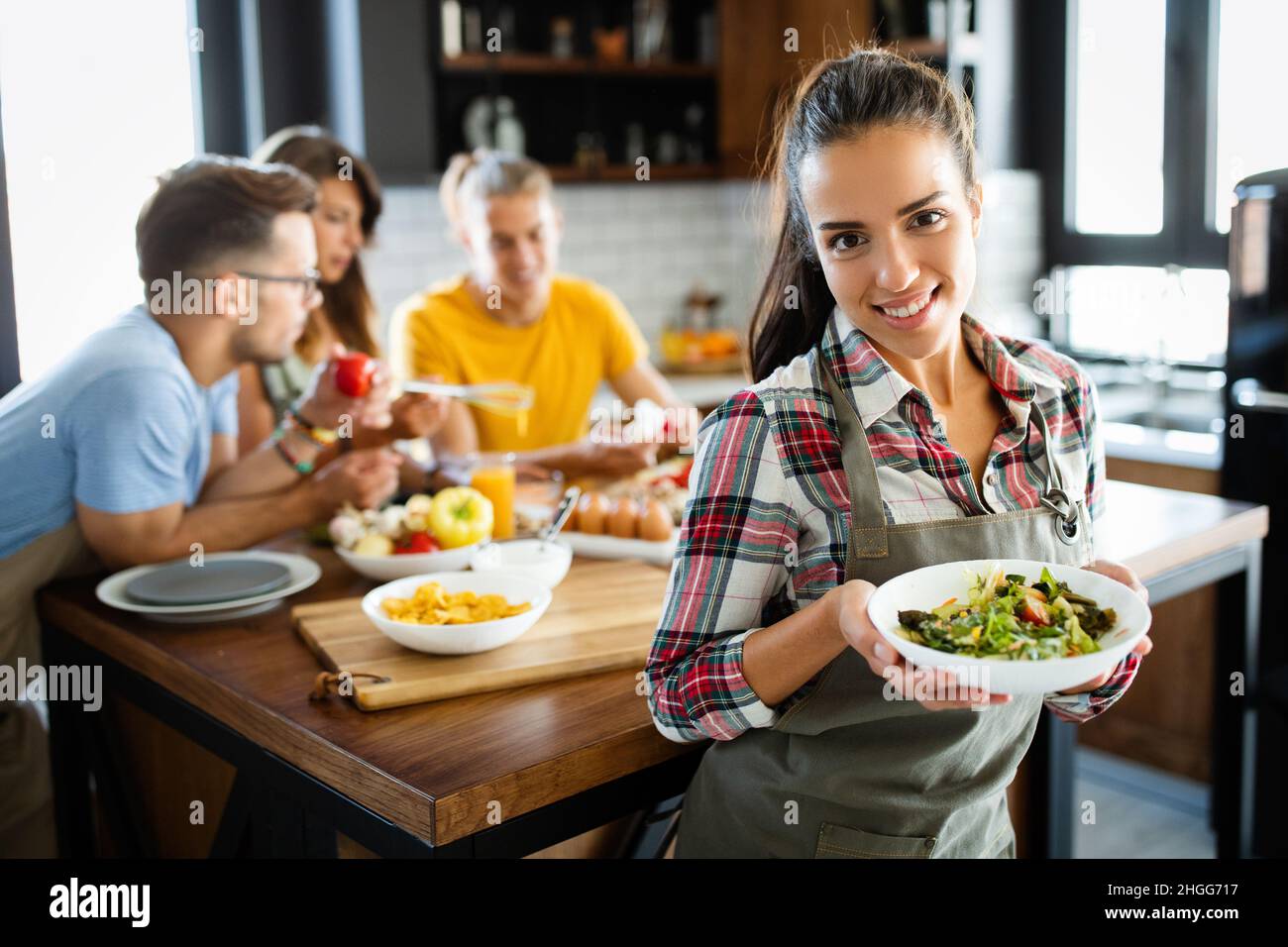 Group of happy friends laughing and talking while preparing meals in ...