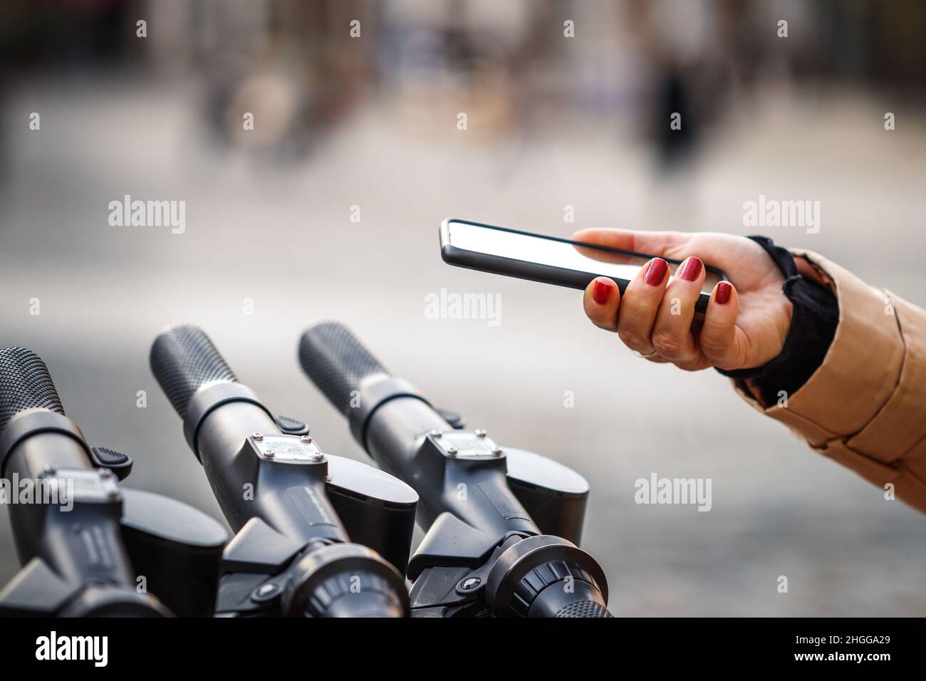 Woman scan QR code by smart phone to unlock and rent electric push ...