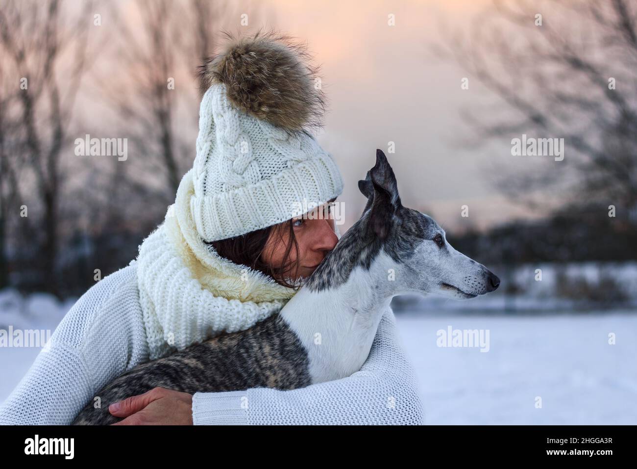 Woman embracing and kissing her dog in winter sunset. Friendship ...