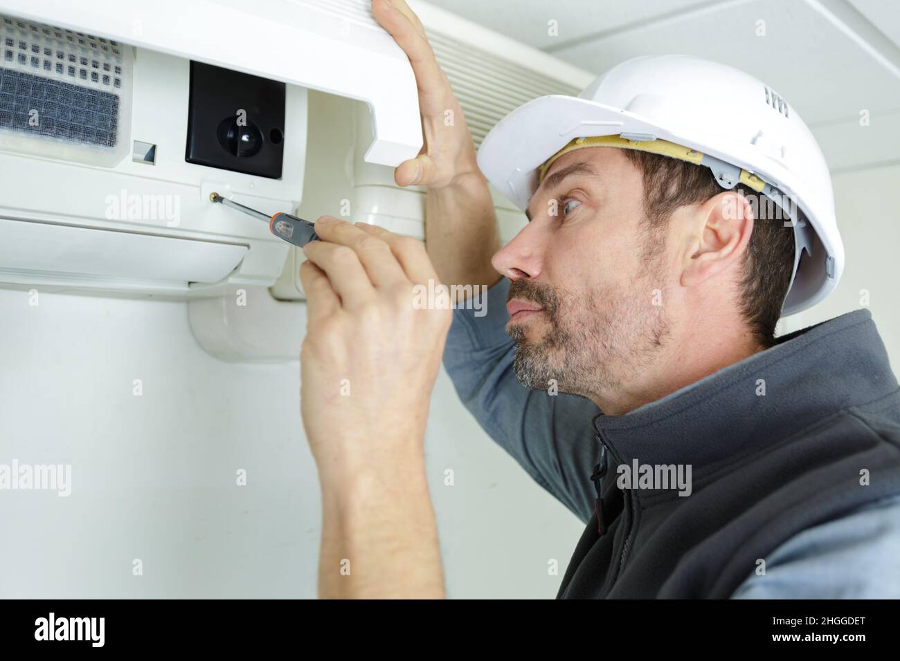 male air conditioning technician using a screw driver Stock Photo - Alamy