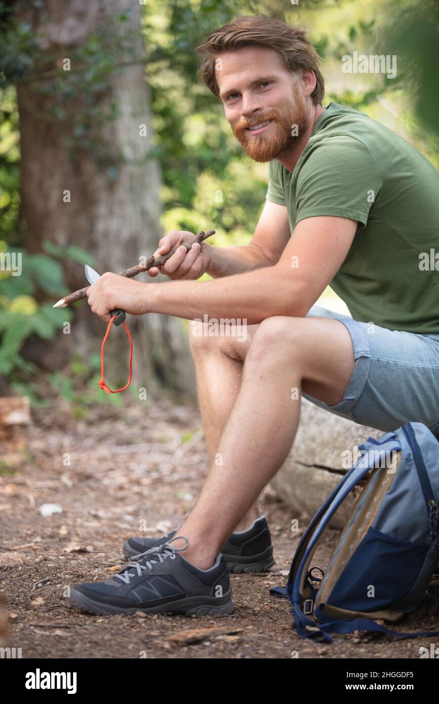man is sharpening stick with the help of knife Stock Photo - Alamy
