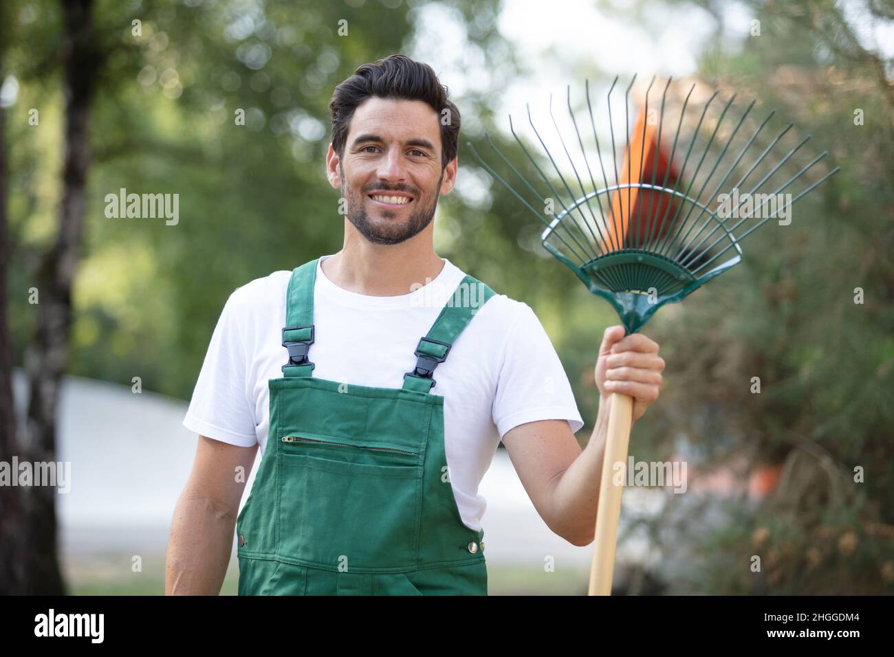 portrait of young man holding rake smiling Stock Photo - Alamy