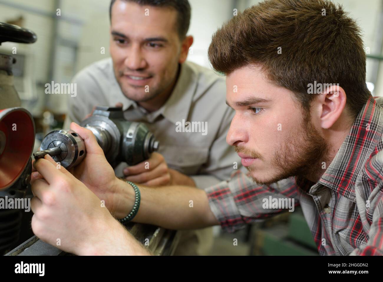 two men working together to operate machine drill Stock Photo - Alamy