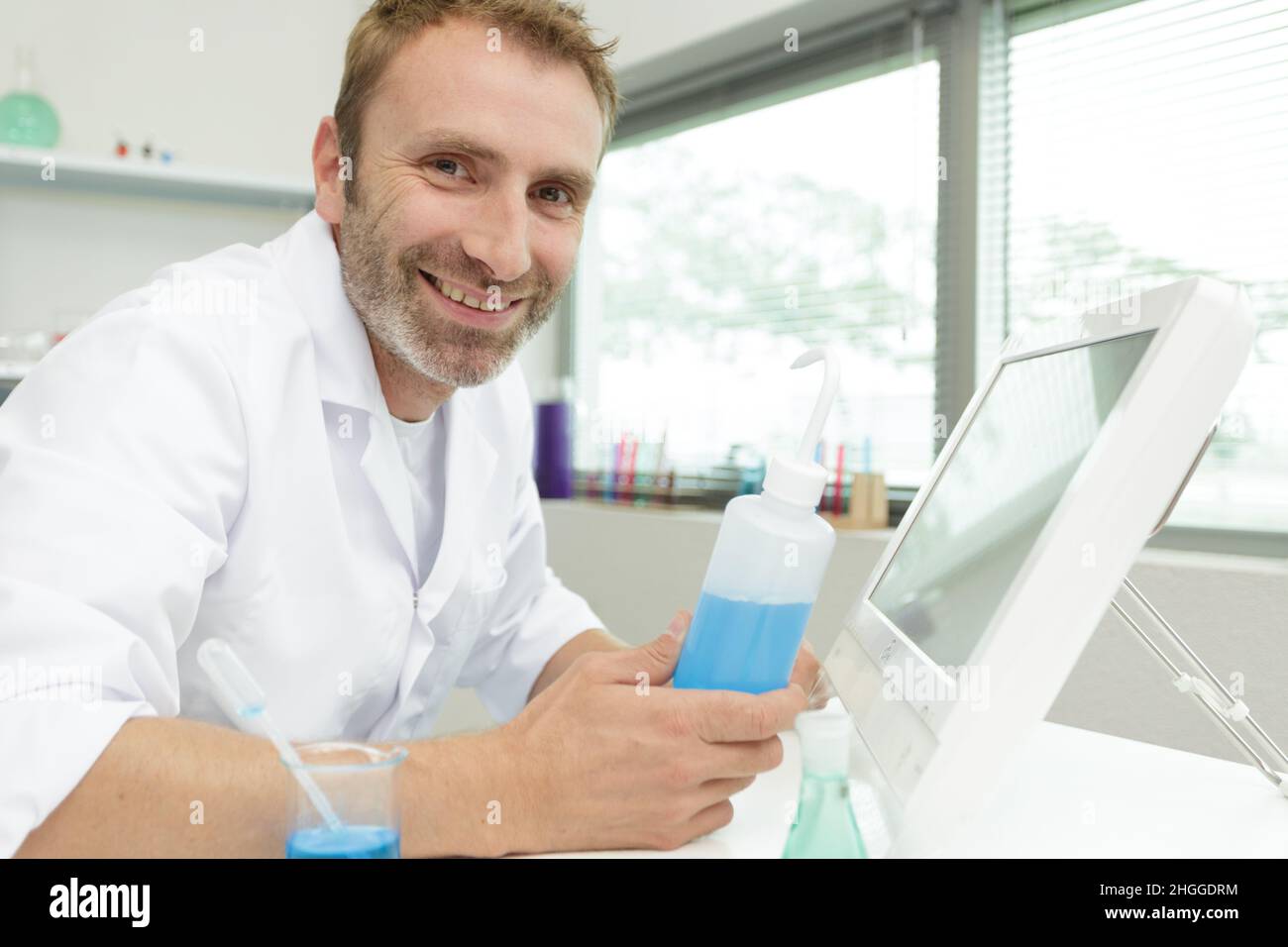 lab-assistant conducts experiments pouring blue liquid from a test tube ...