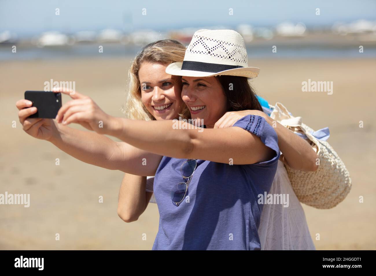 Female Friends Taking Selfies On The Beach With A Smartphone Stock