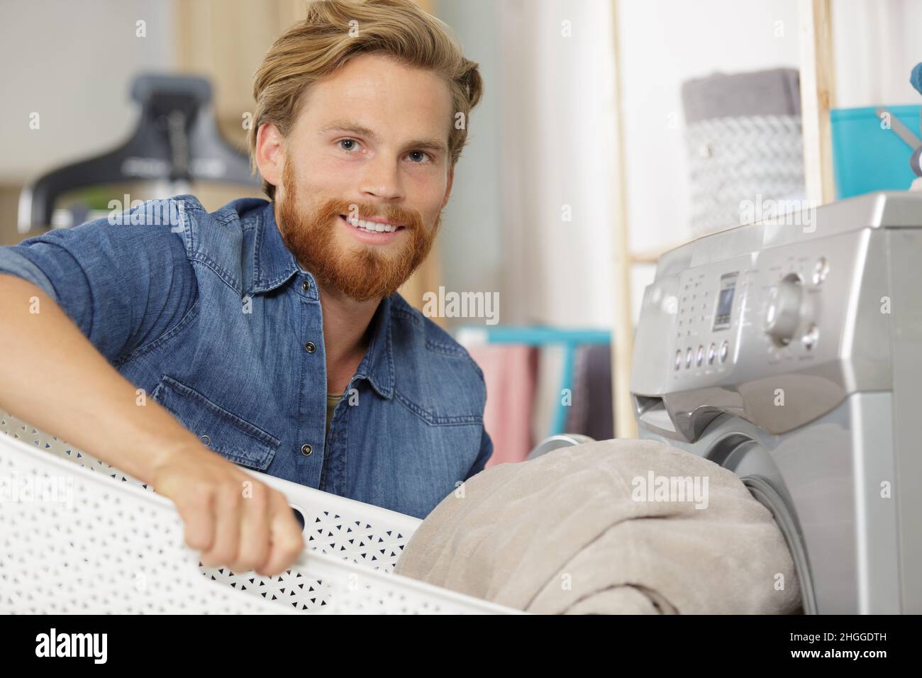 young man loads the laundry into the washing-machine Stock Photo - Alamy