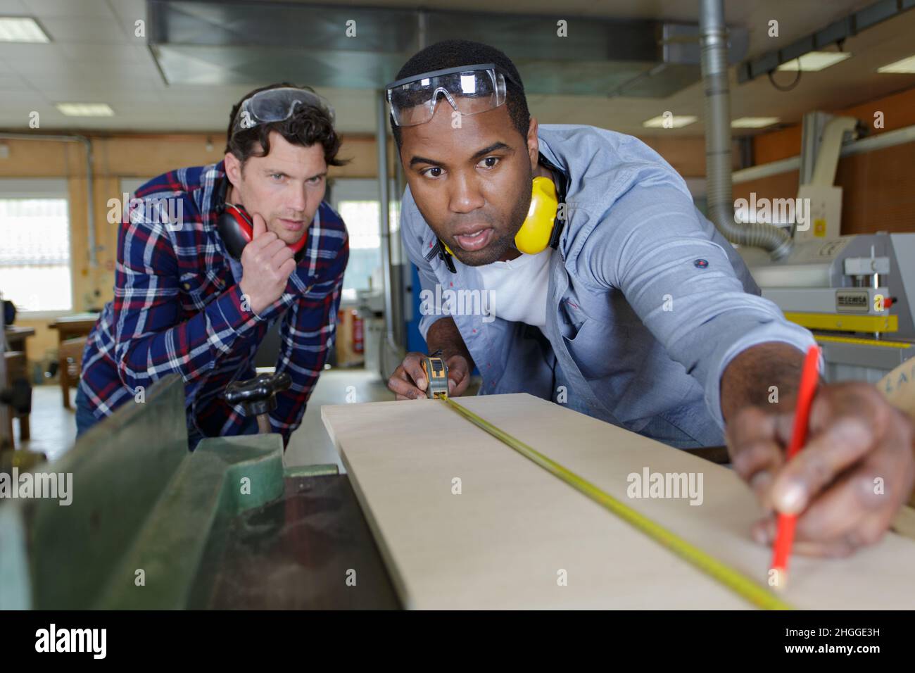 two men in carpentry workshop measuring board Stock Photo - Alamy