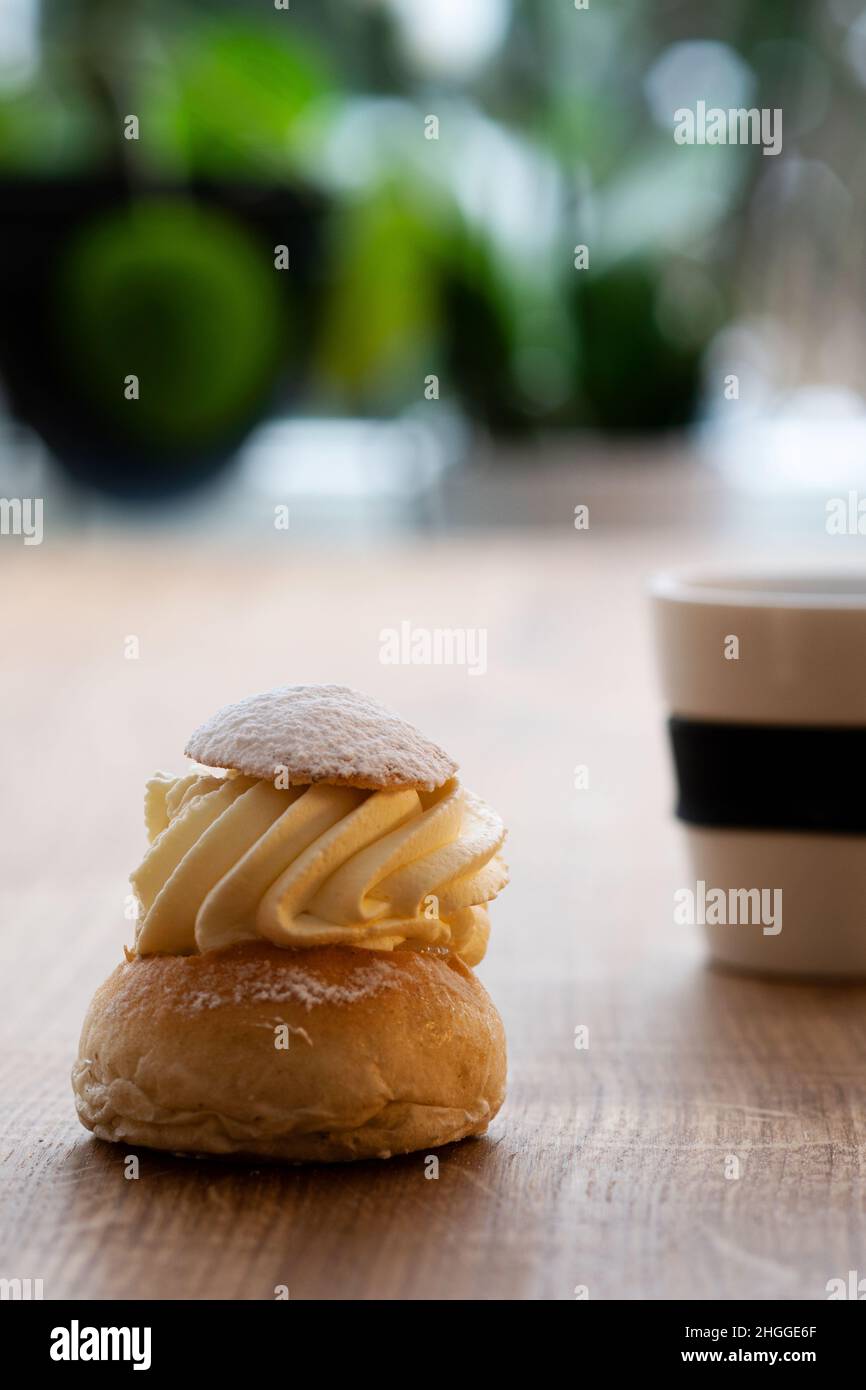 Coffee mug and traditional Swedish pastry, the semla, on wooden table ...
