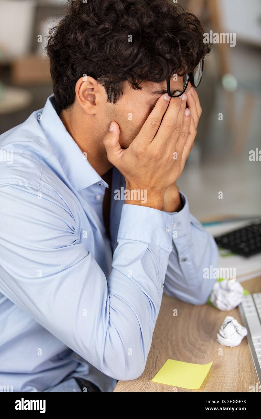 stressed office man in desk covering face with hands Stock Photo - Alamy
