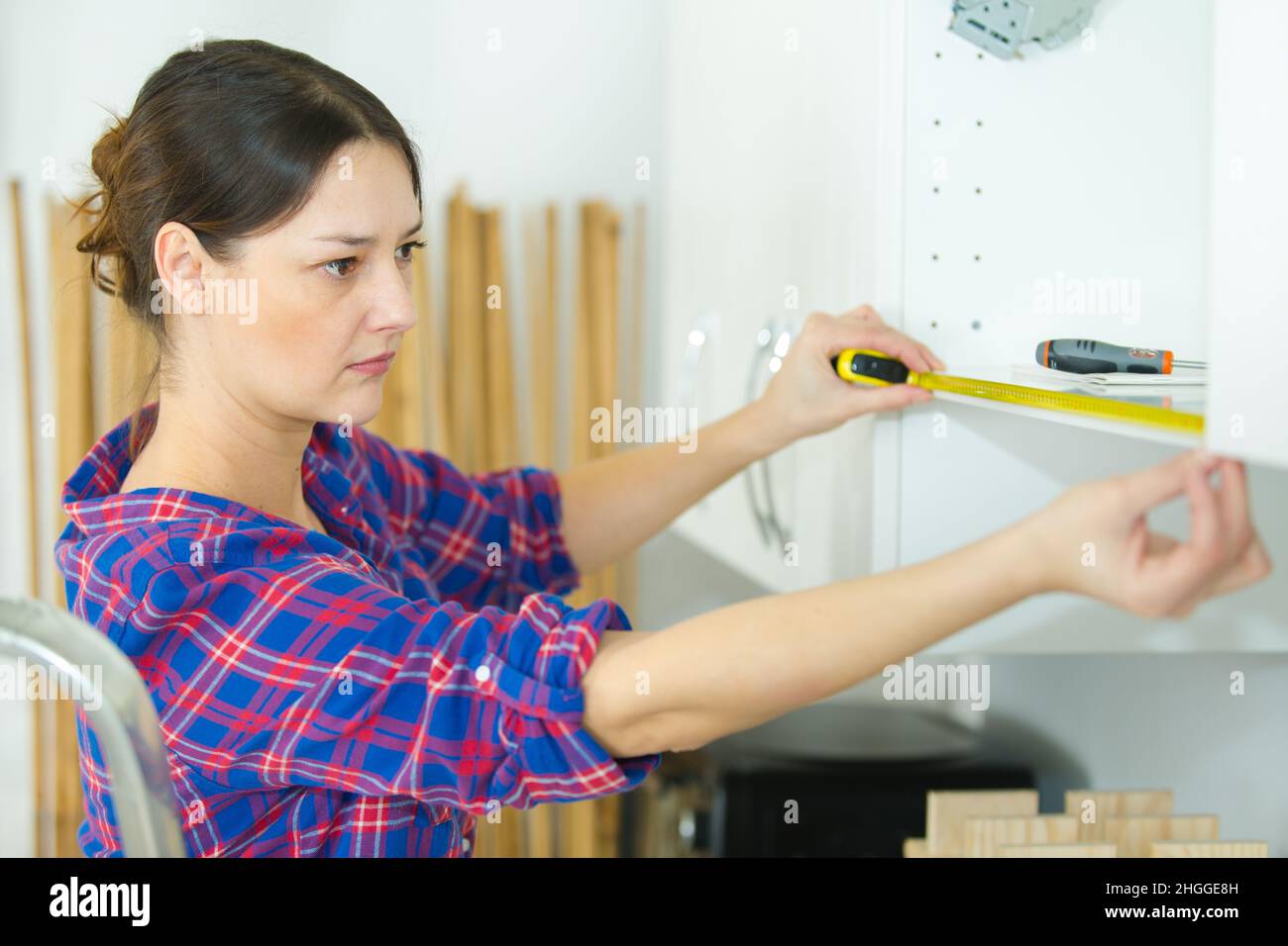 portrait of woman measuring cupboard Stock Photo - Alamy