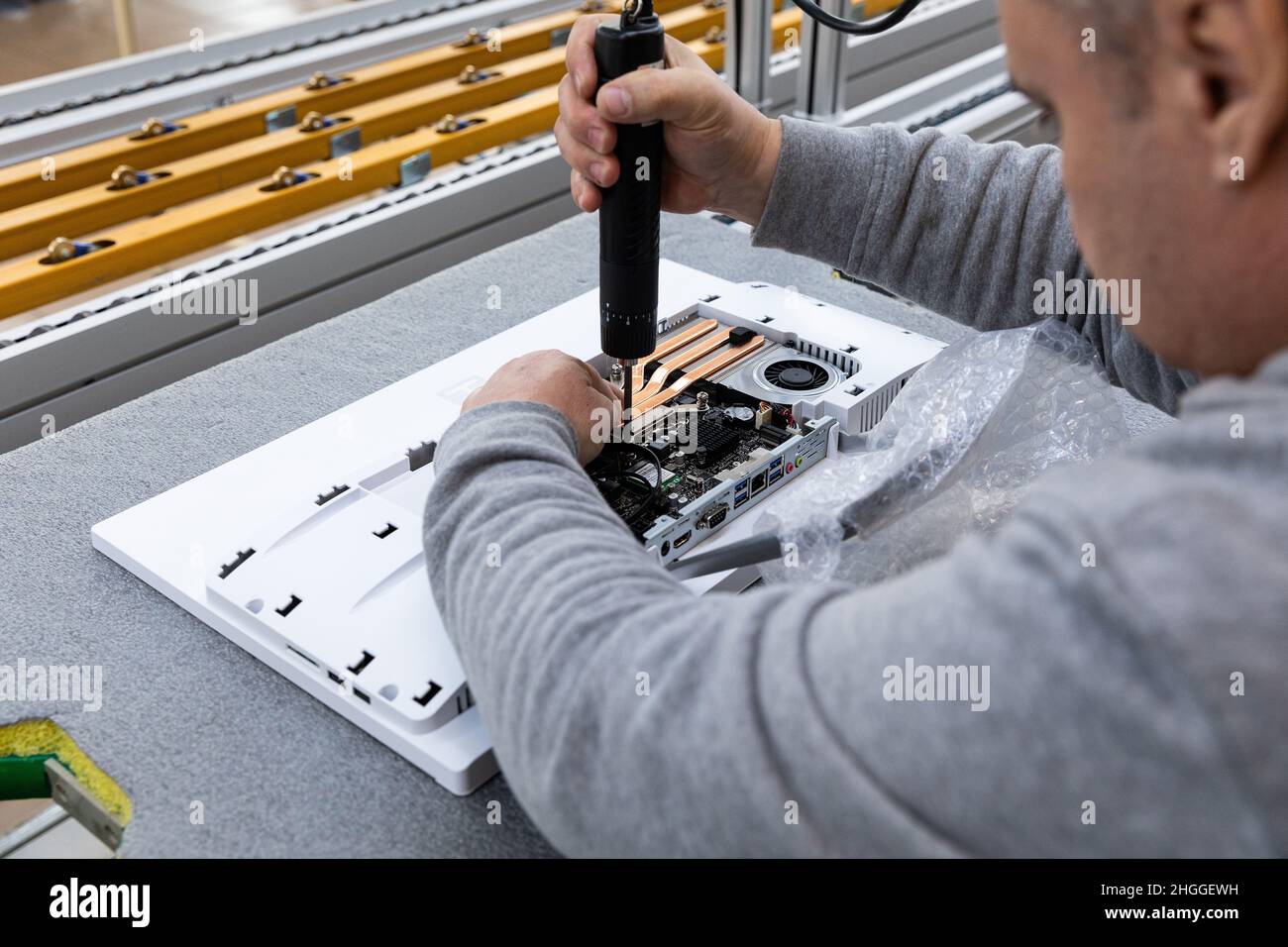 Photo Of An Adult Man In A Gray Sweater Who Assembles A Computer Monitor System Block On An