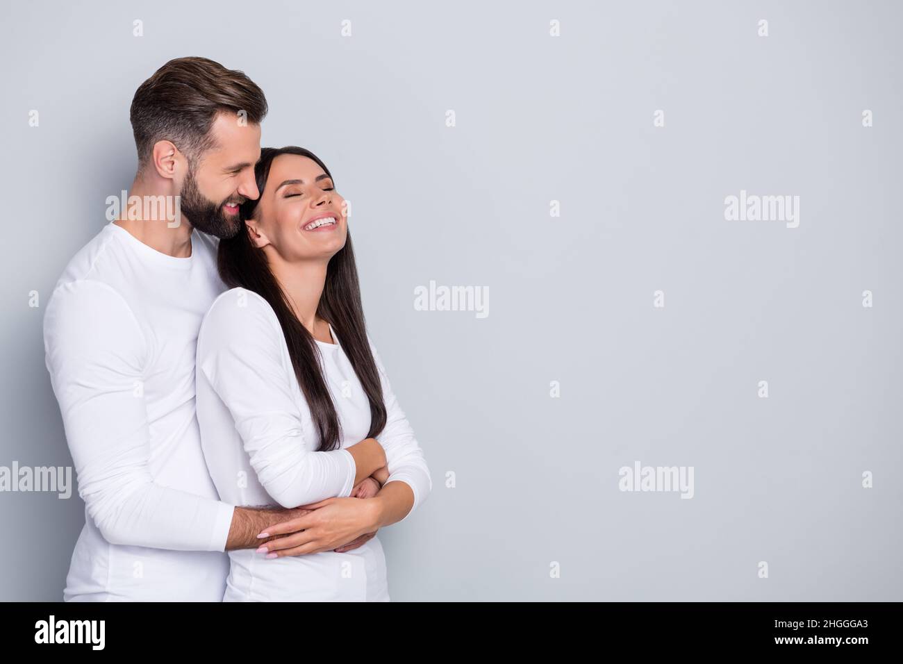 Profile photo of impressed young couple hug near empty space wear white ...
