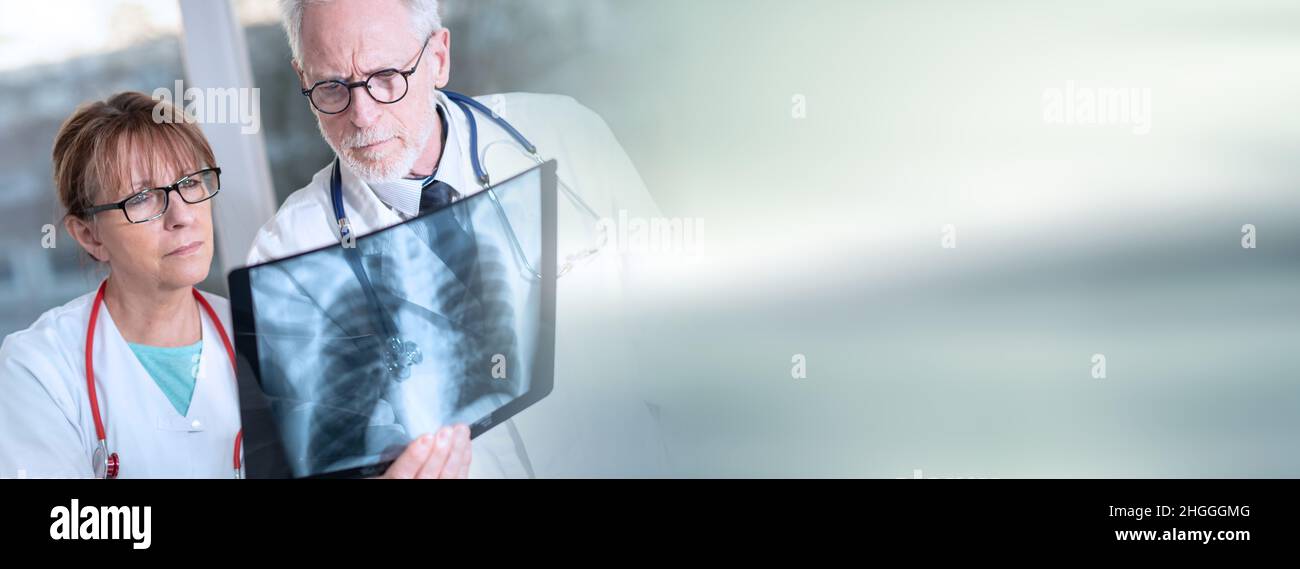 Two doctors examining x-ray report in medical office; panoramic banner ...