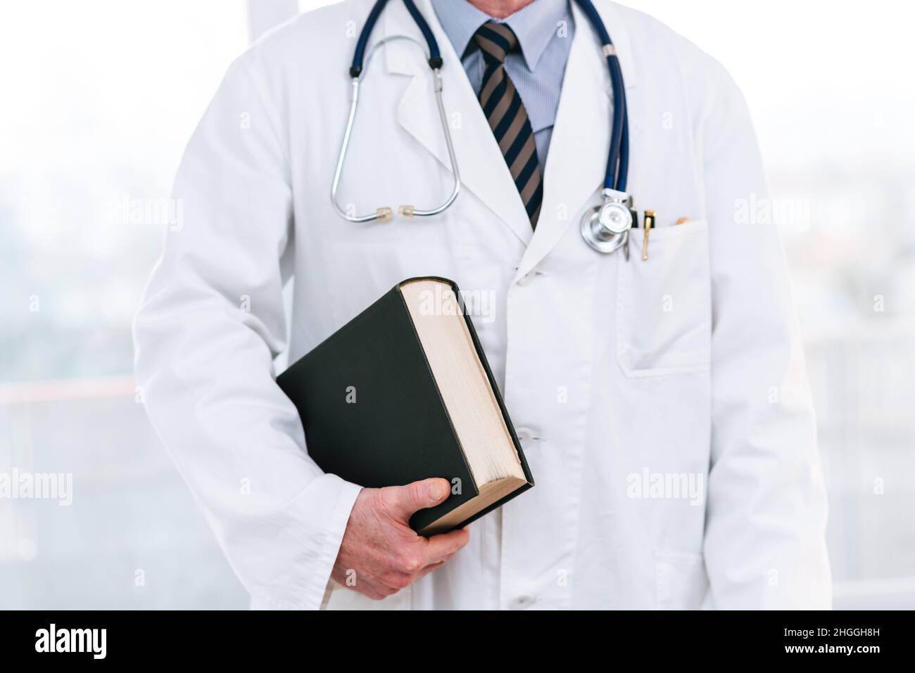 Doctor standing and holding a medical textbook Stock Photo - Alamy