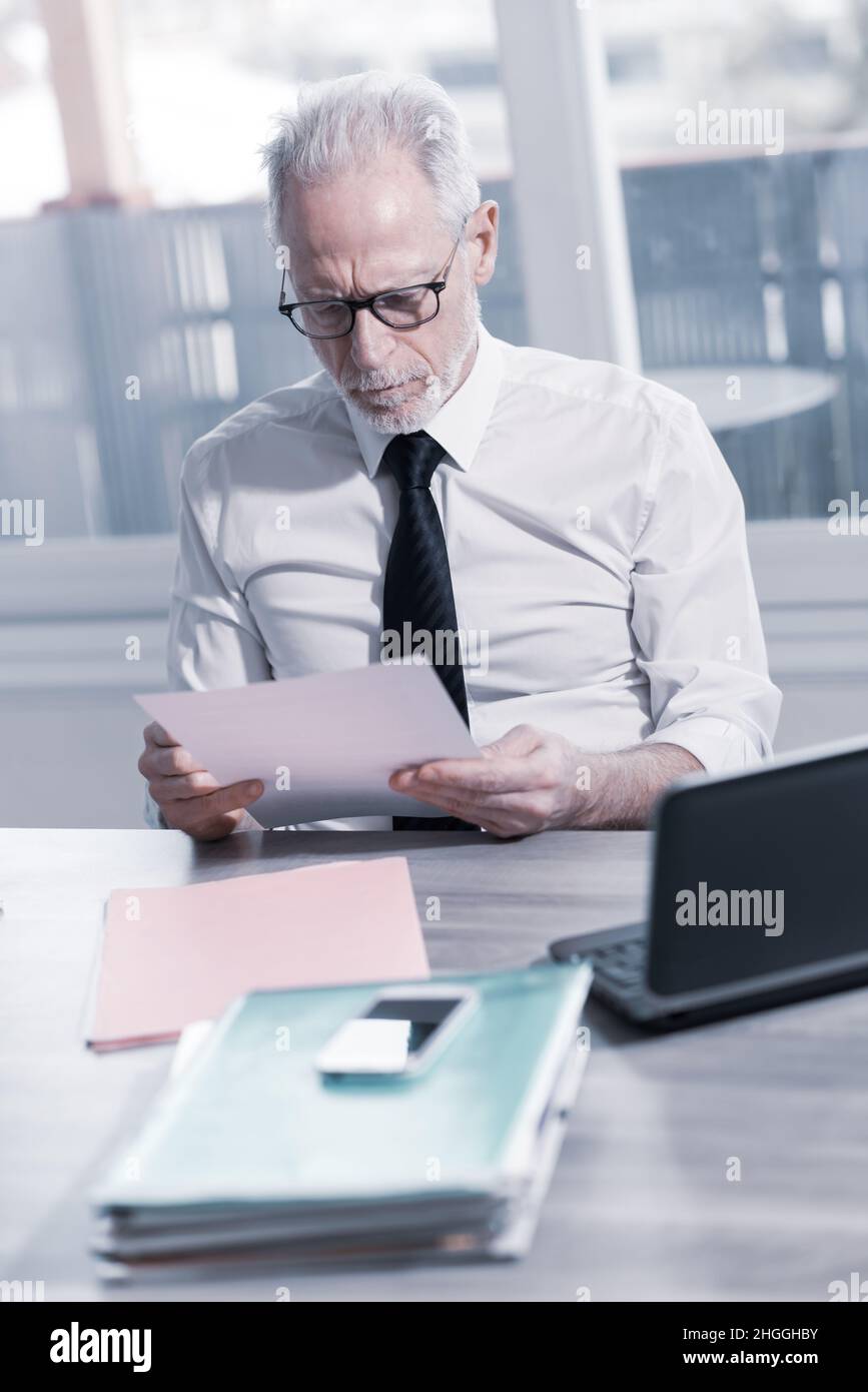 Serious businessman checking corporate paperwork hi-res stock ...