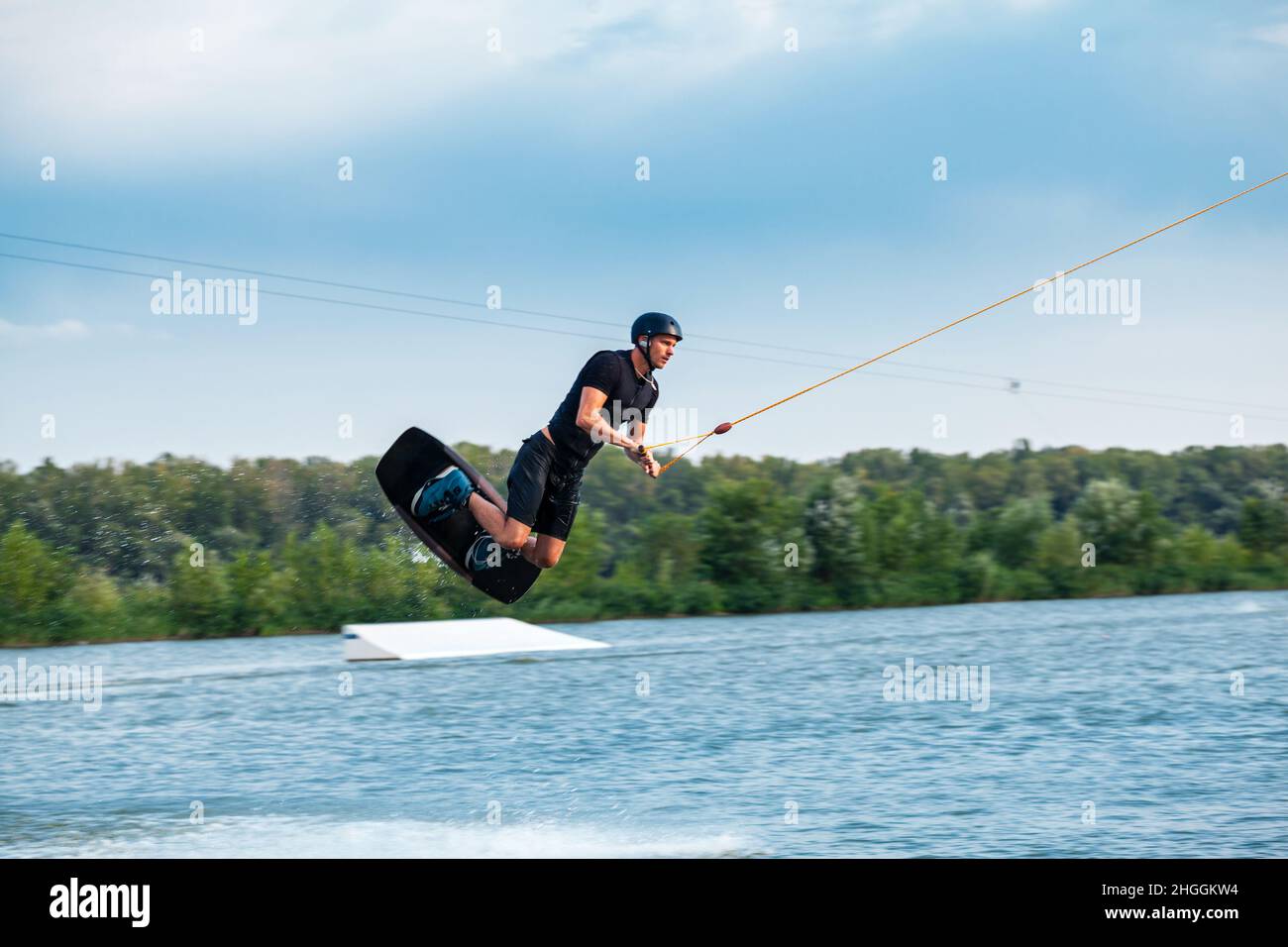 Man practicing technique of jumping over water during wakeboarding ...