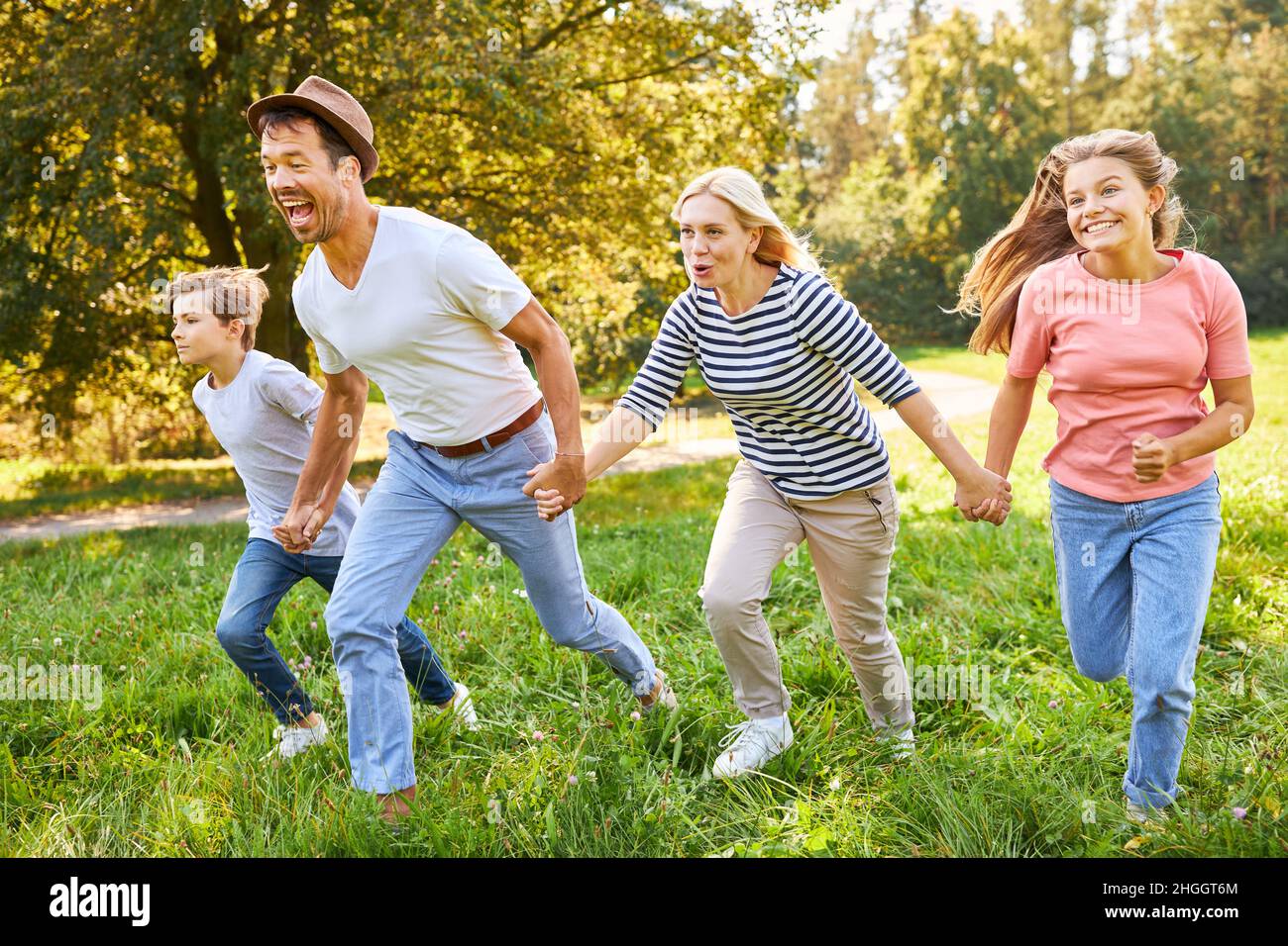 Happy parents with daughter and son have fun running across a summer ...