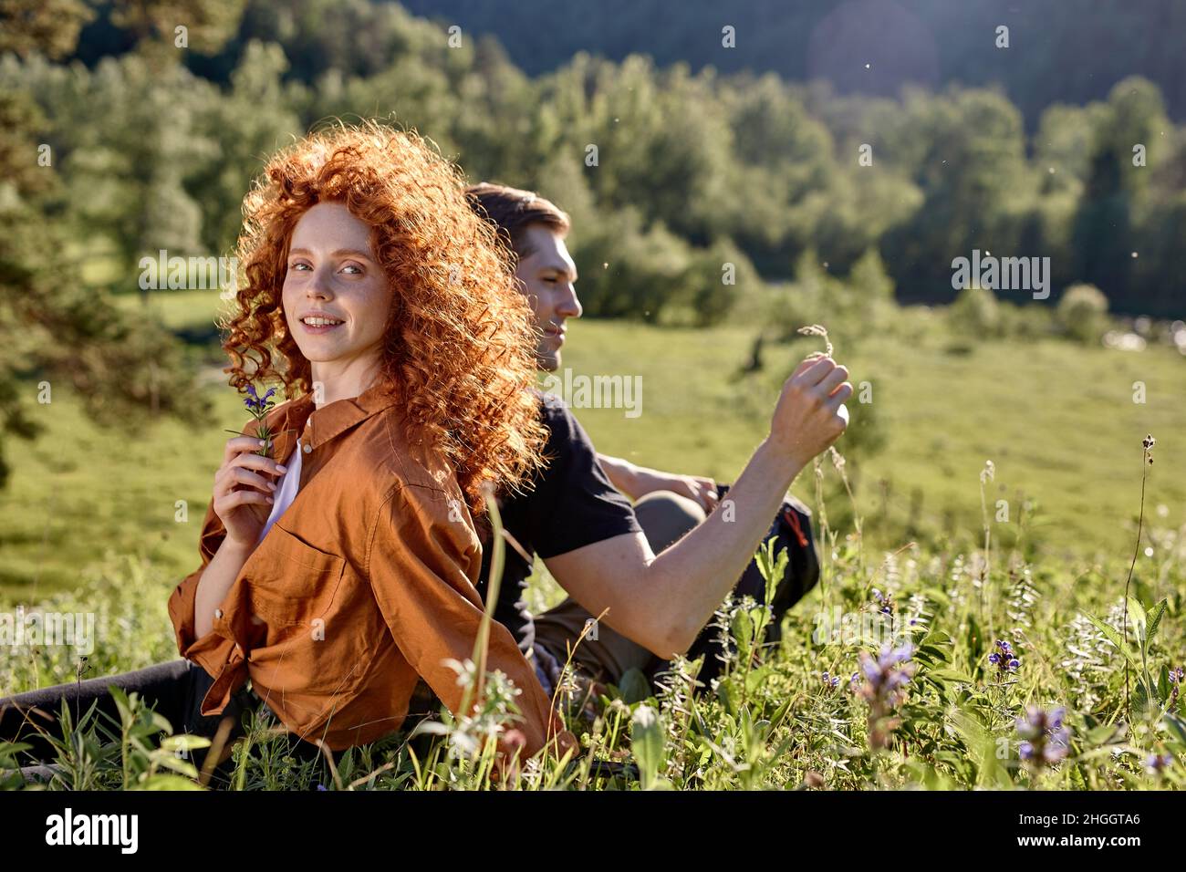 Beautiful couple in the forest. Young woman and man sitting on grass ...