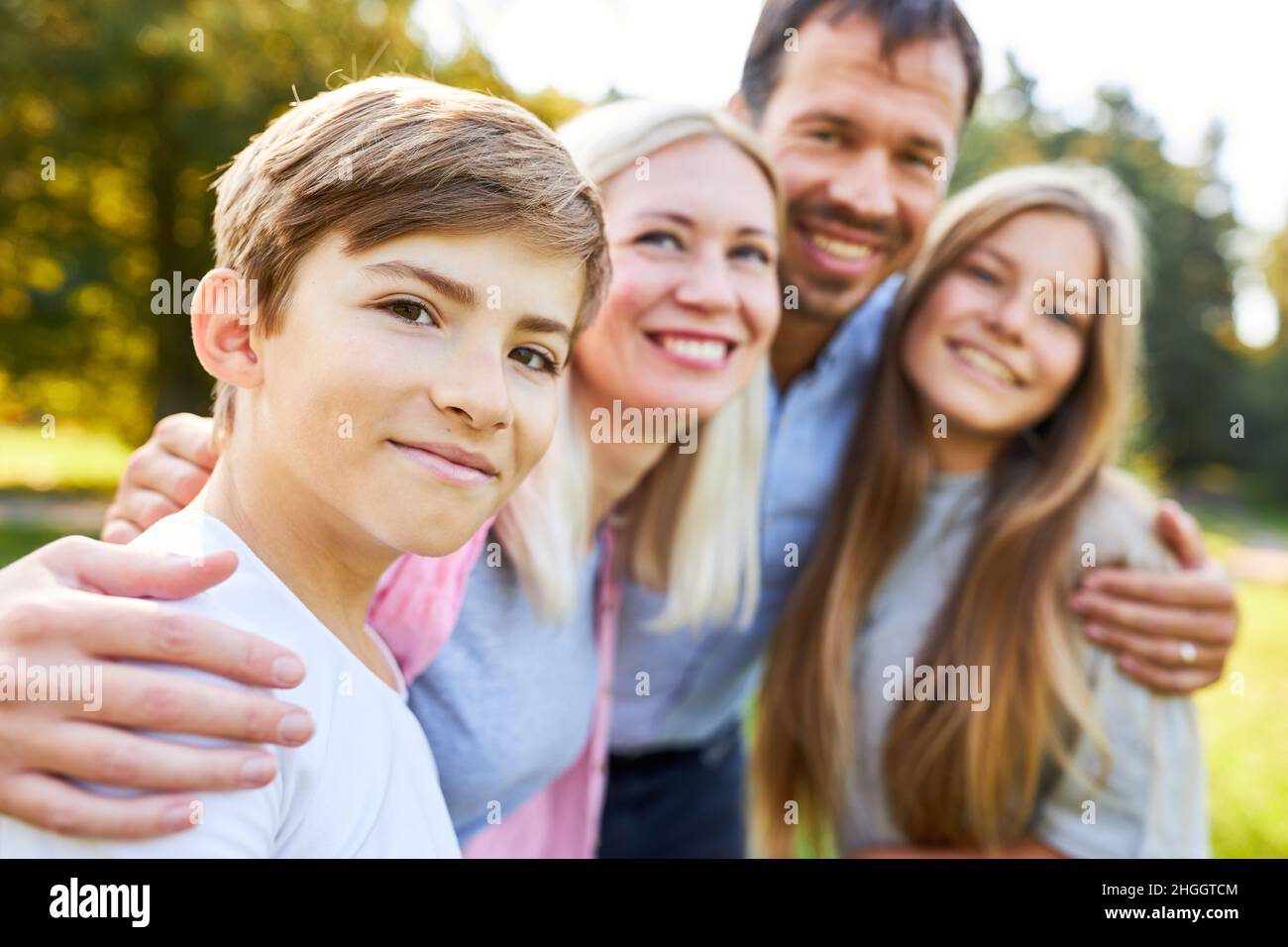Happy family with parents and two children hugging in the garden in ...