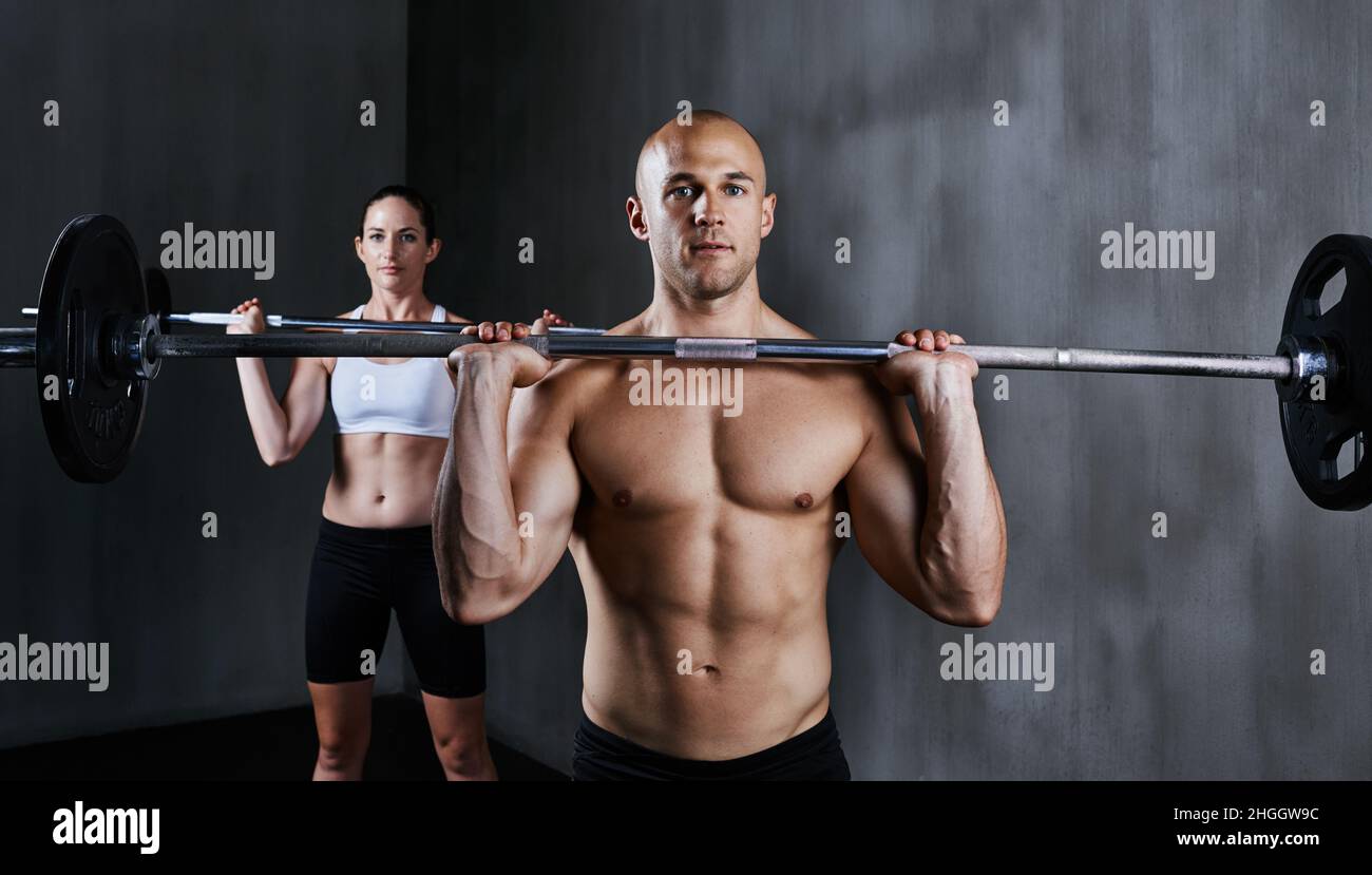 Shaping up at the gym. Shot of two people lifting barbells during a gym ...