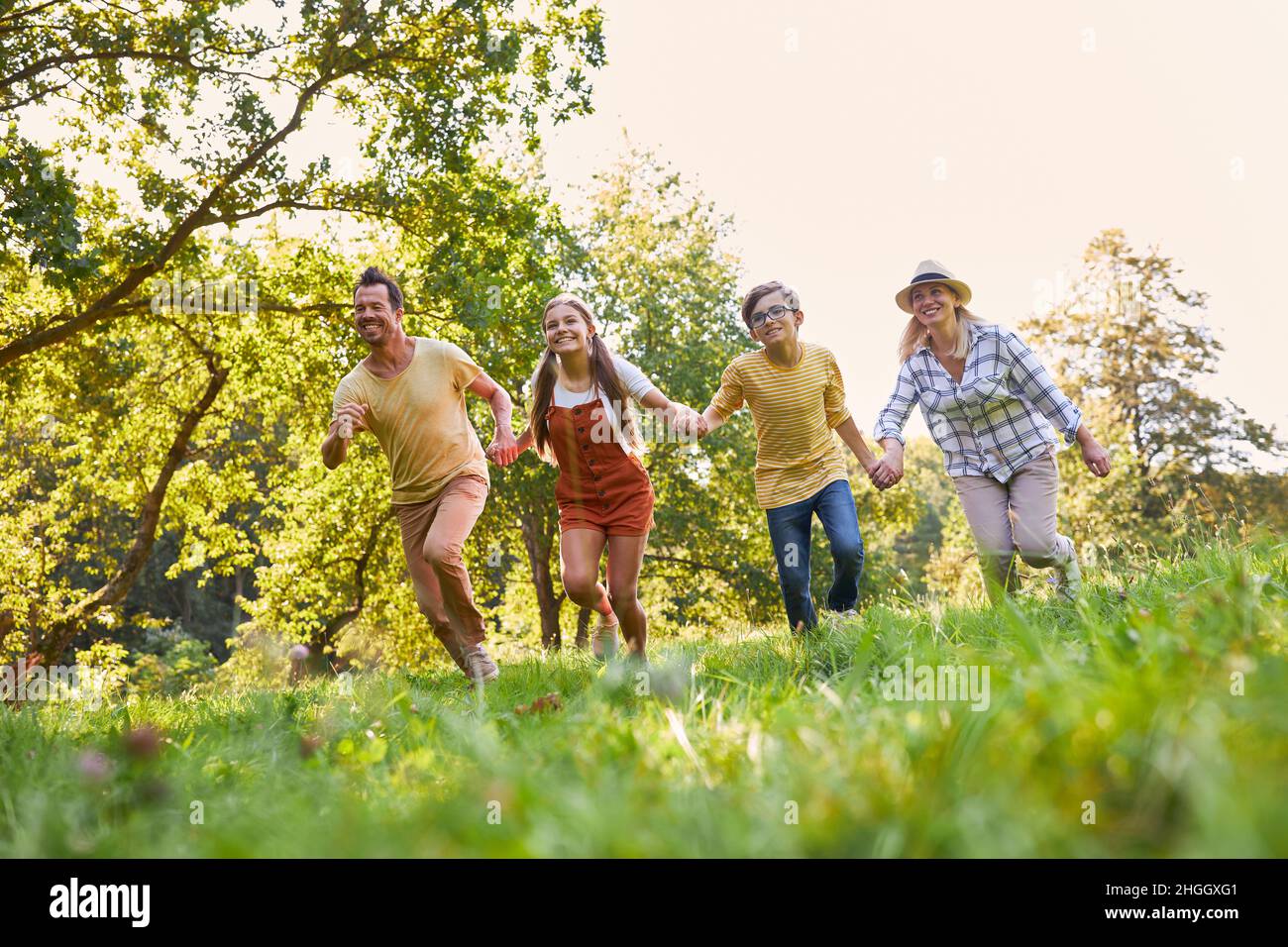 Happy family with two children running holding hands across a summer ...