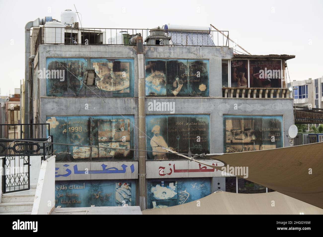 Faded and windswept billboards on a building in Aqaba Jordan depicting ...