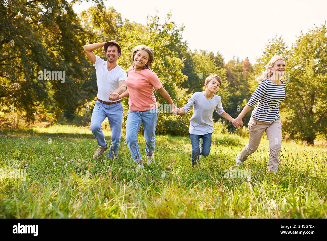 Happy family and two children in motion on a meadow in nature in summer ...