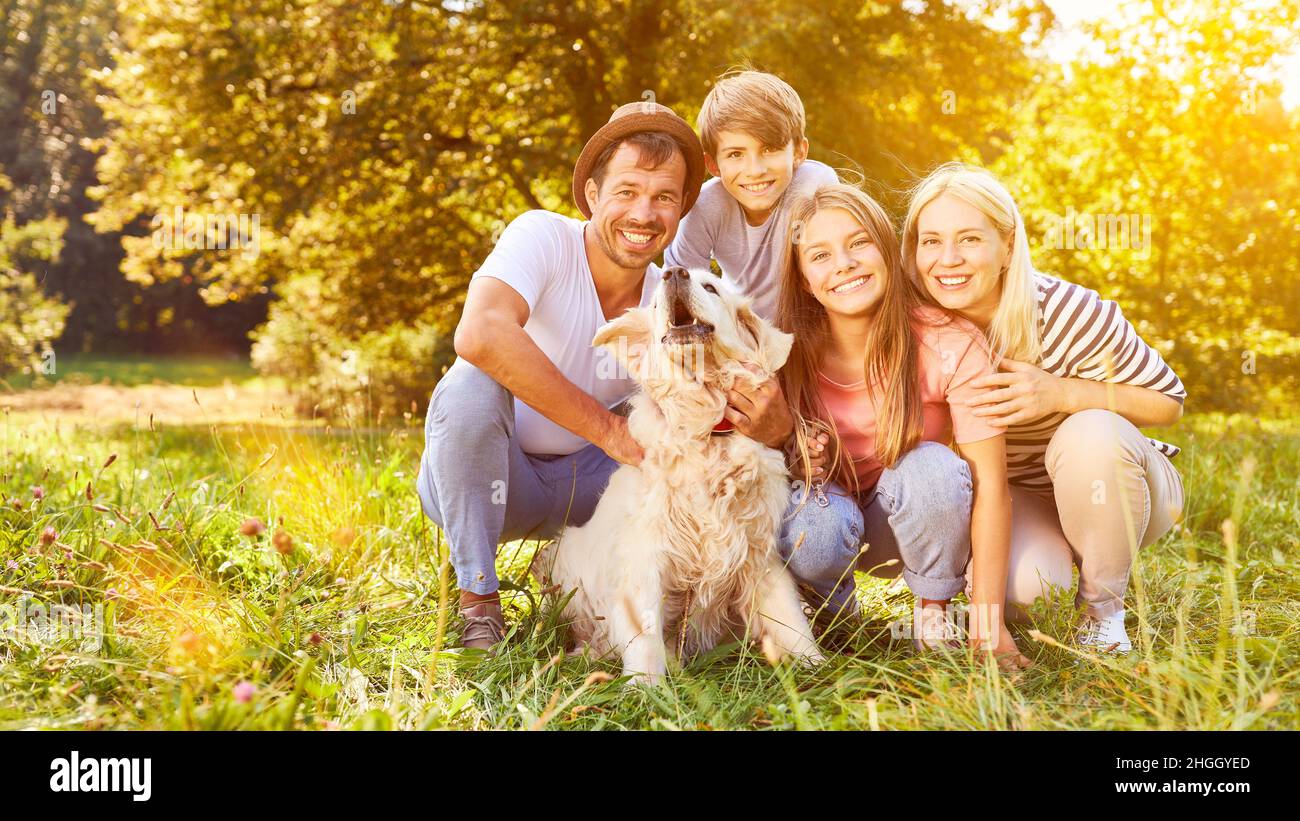 Portrait of a happy family with two children and a dog in the garden in ...