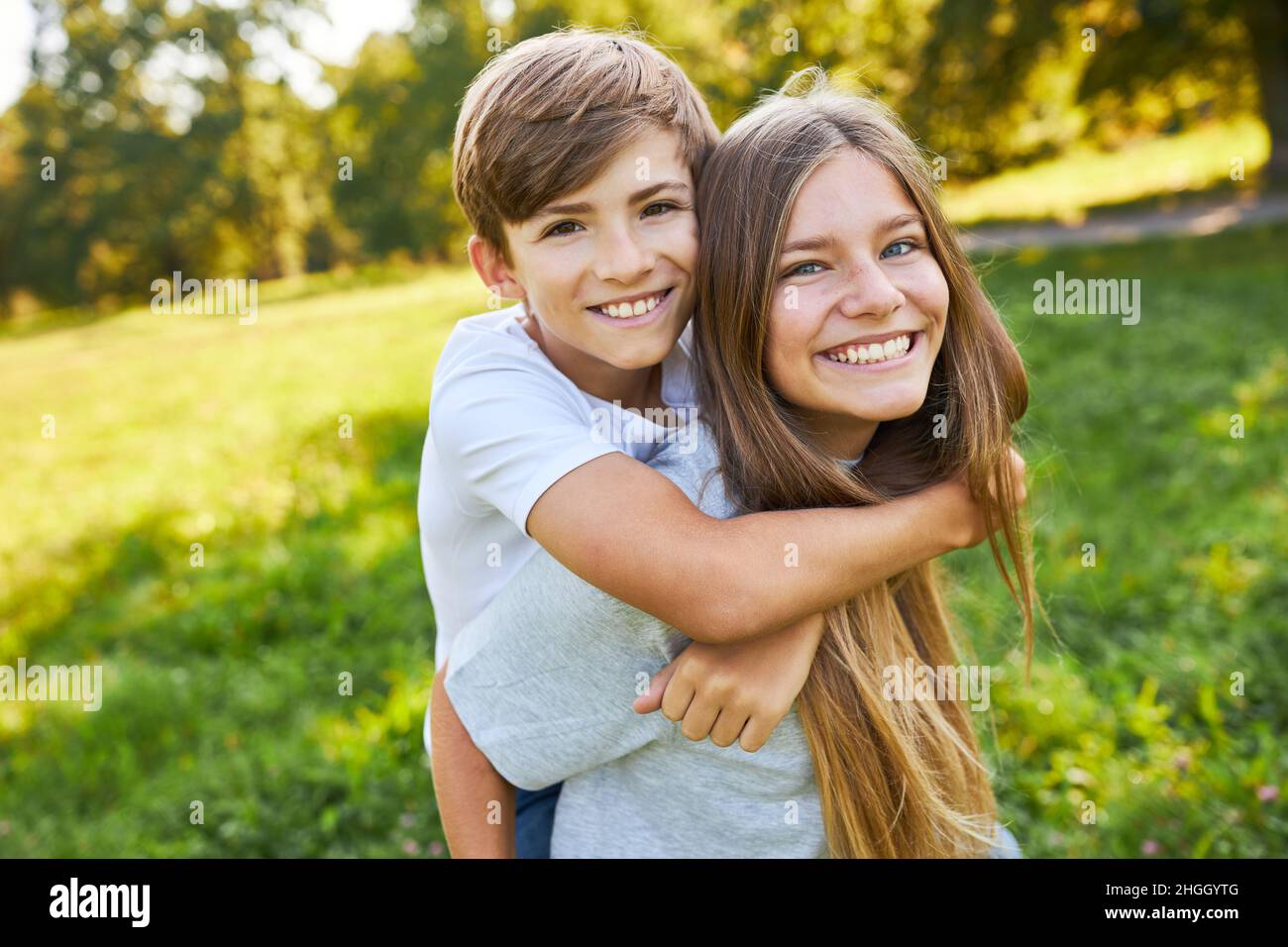 Boy and girl as happy siblings carrying piggyback in the garden Stock ...